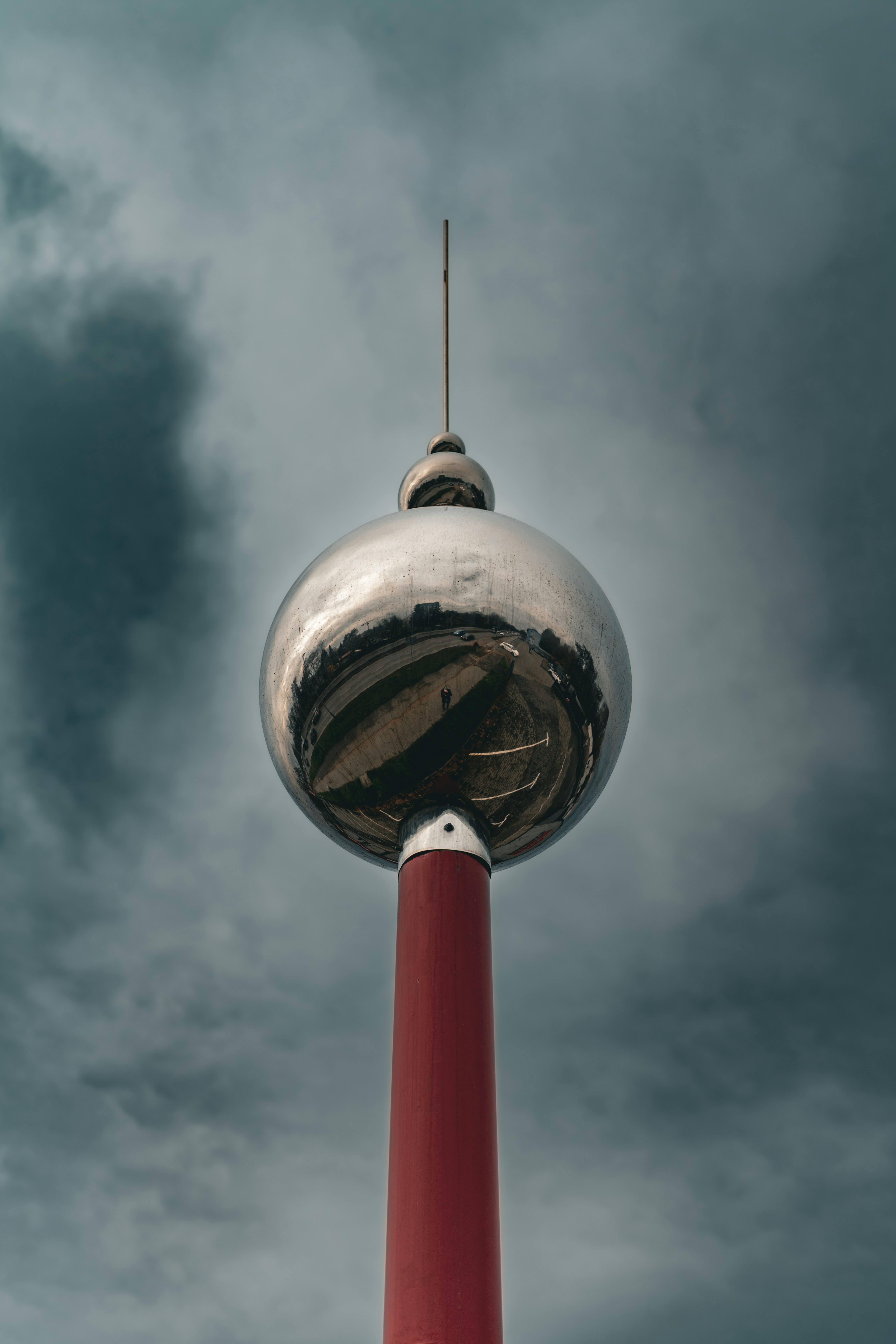 Crimson Pole Crowned by a Reflective Sphere Under a Moody Sky