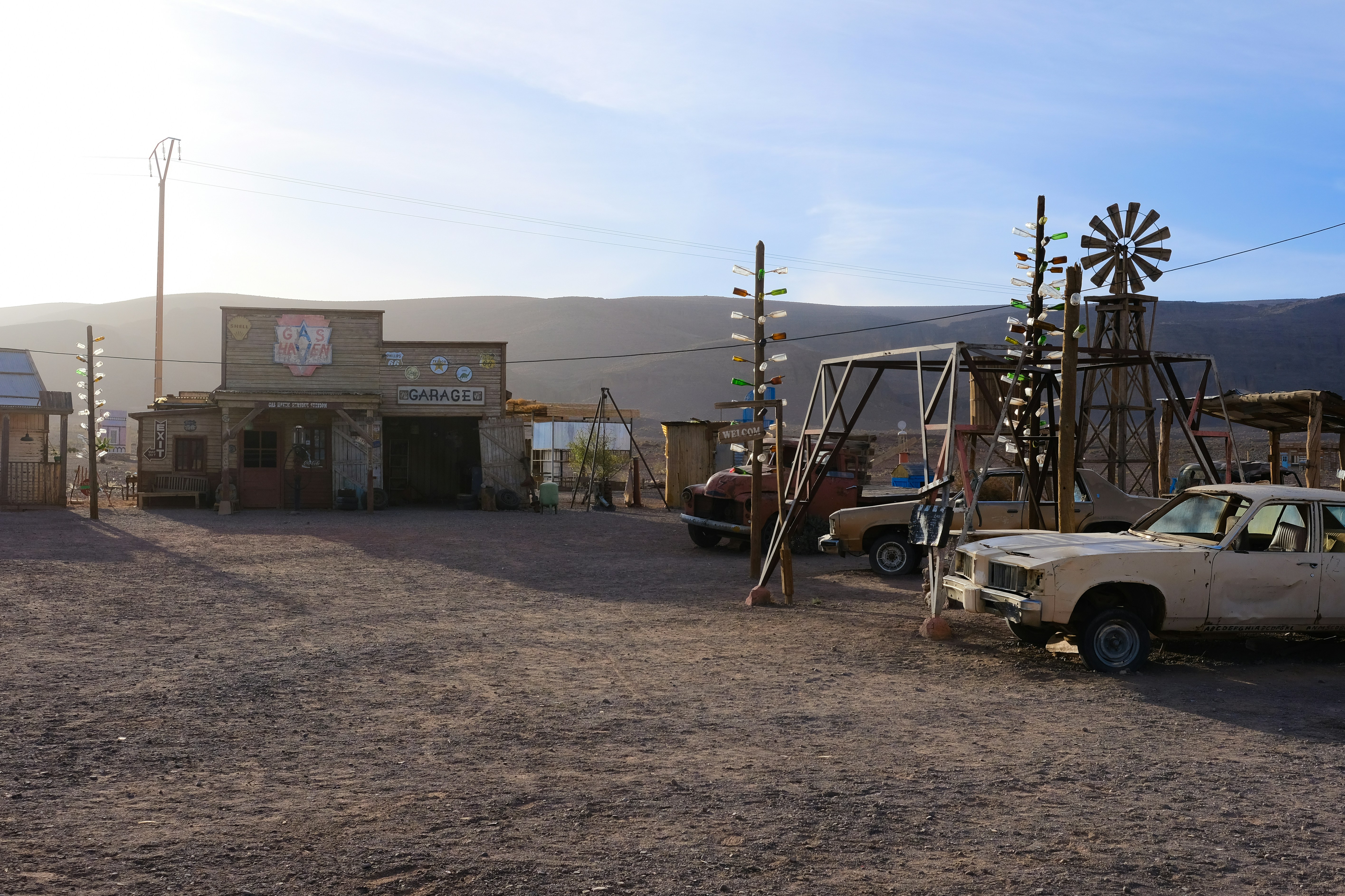 Desert Outpost at Dusk: Rusted Cars, Windmills, and a Quiet Frontier
