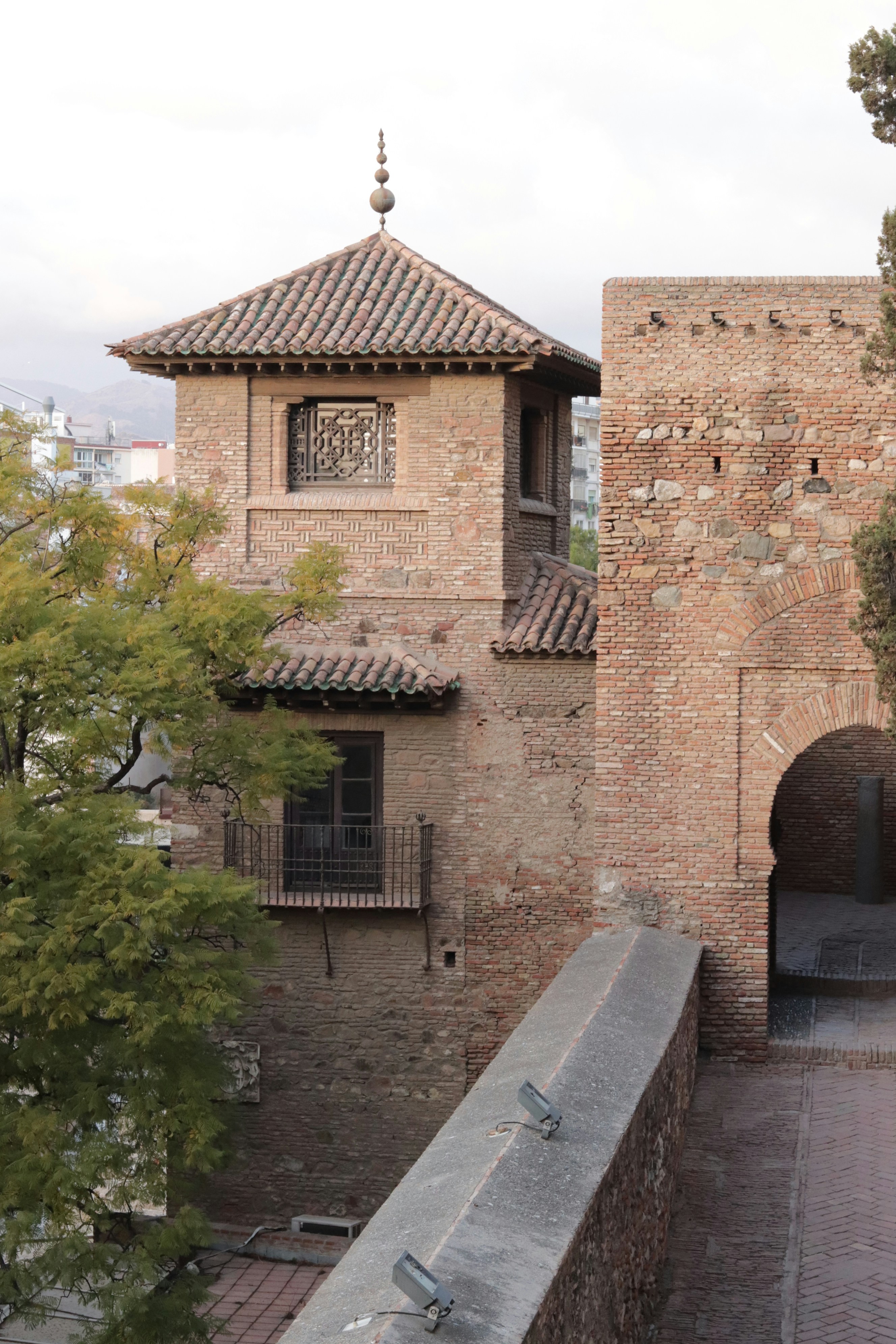 Tiled-Roof Watchtower Rising Beside an Arched Brick Gate