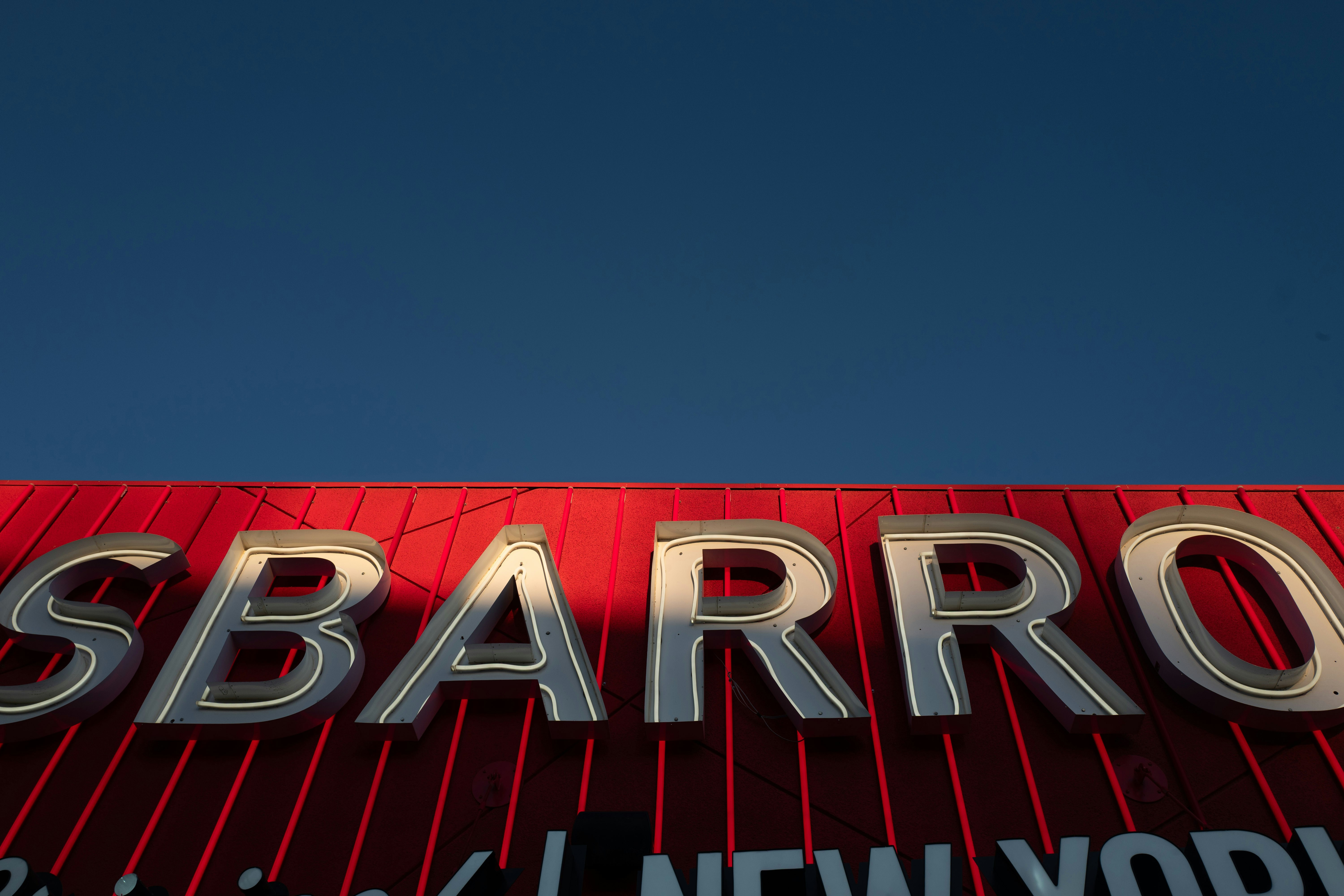 Silver Glyphs on a Red Facade Beneath a Deep Blue Sky