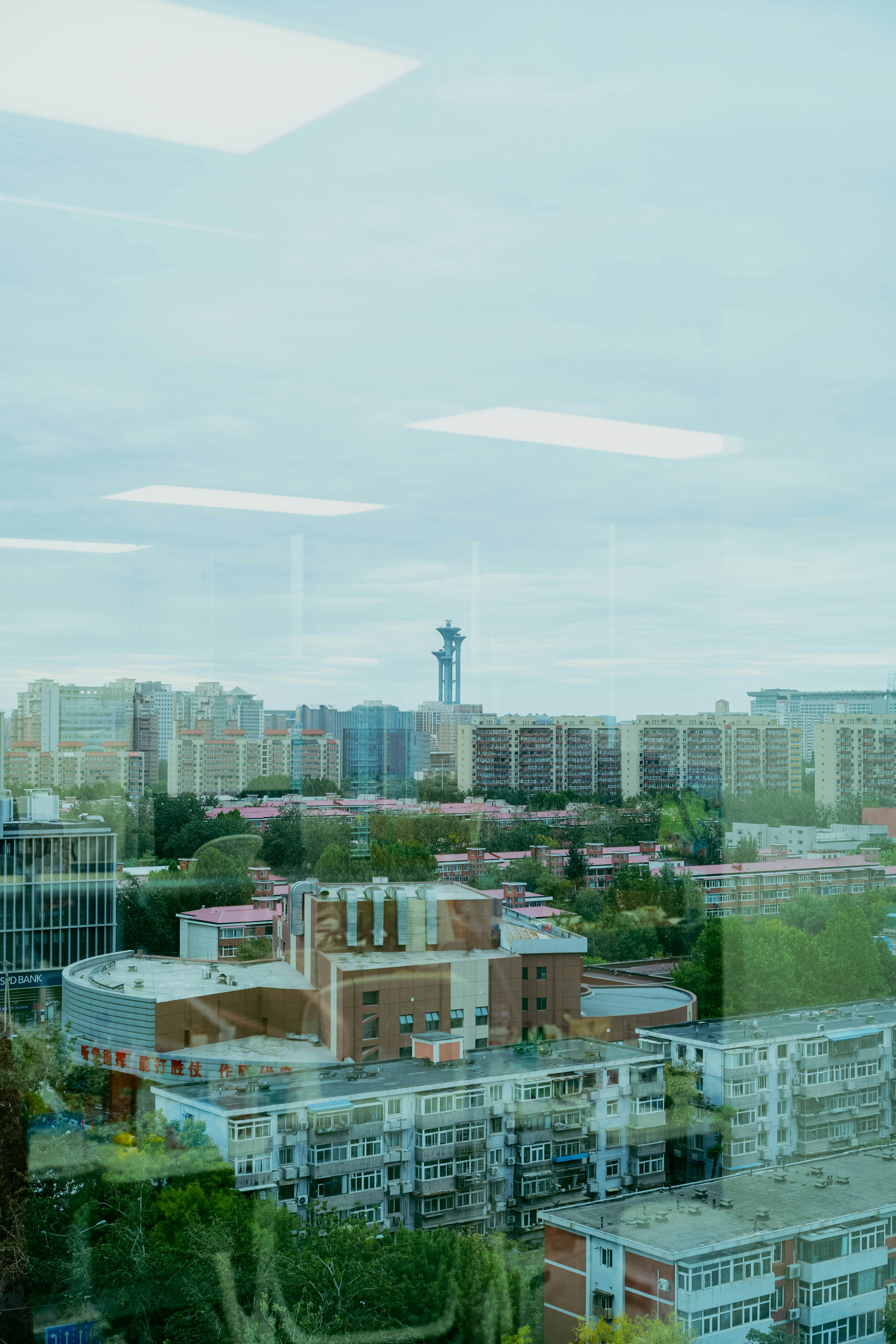 Tower Amid Glass Veil: A Turquoise Cityscape Through a Window