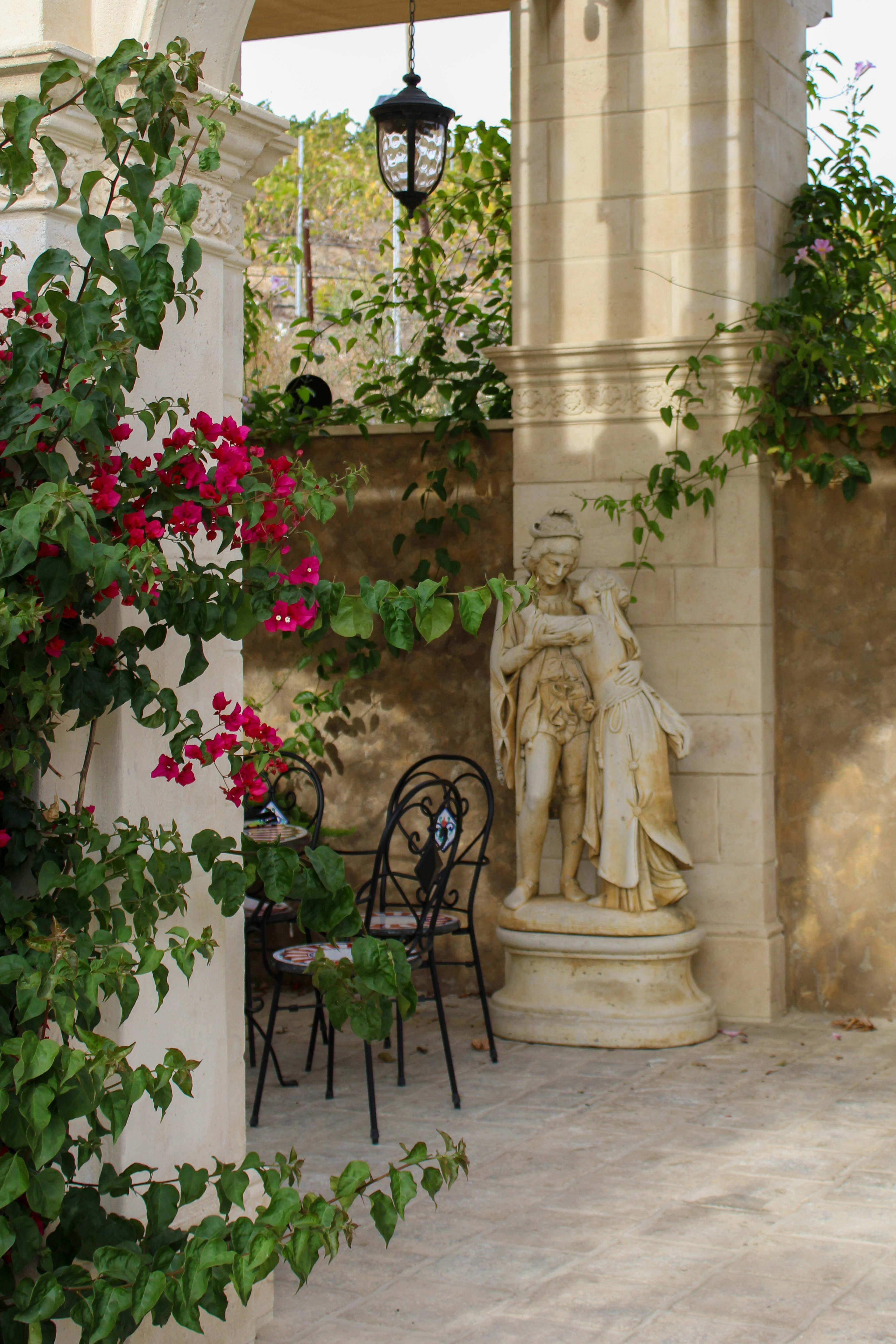 Estatua de piedra y sillas en un patio ajardinado. foto – Imagen de ...