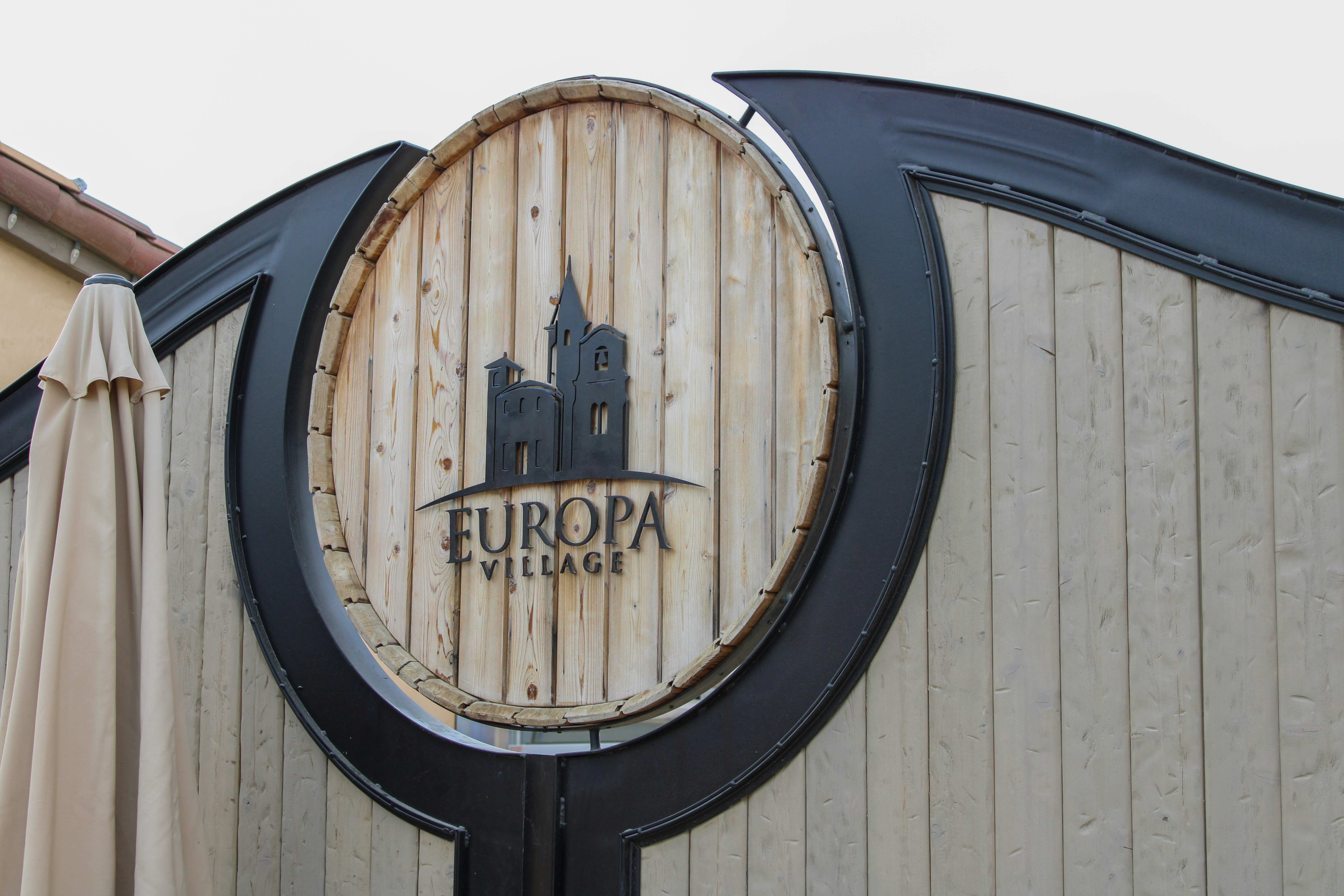 Europa Village Circular Emblem: Timber Ring Framing a Cathedral Silhouette