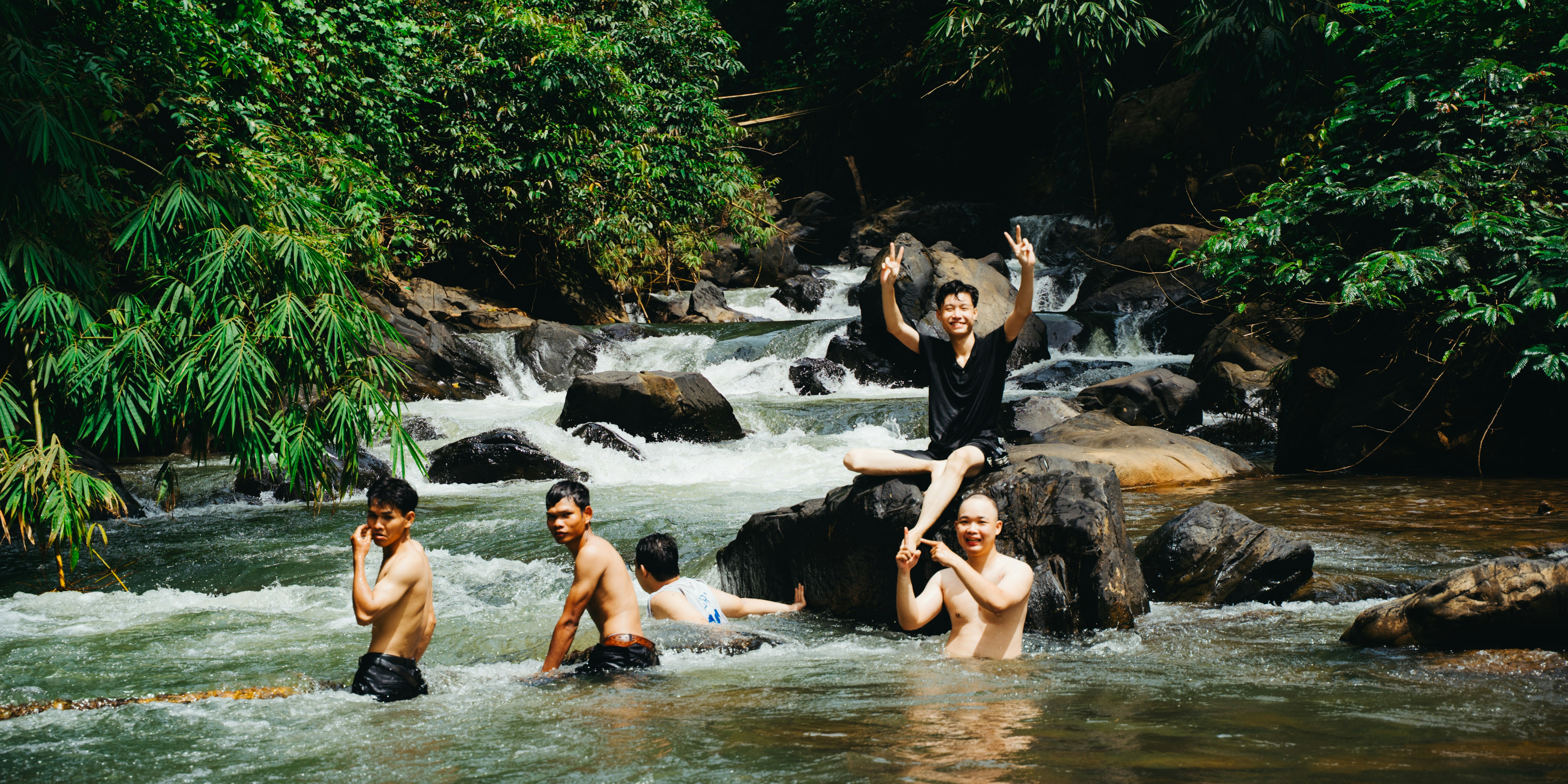 Arms Raised on Jungle River Rock: A Playful Moment Among Moss and Flow