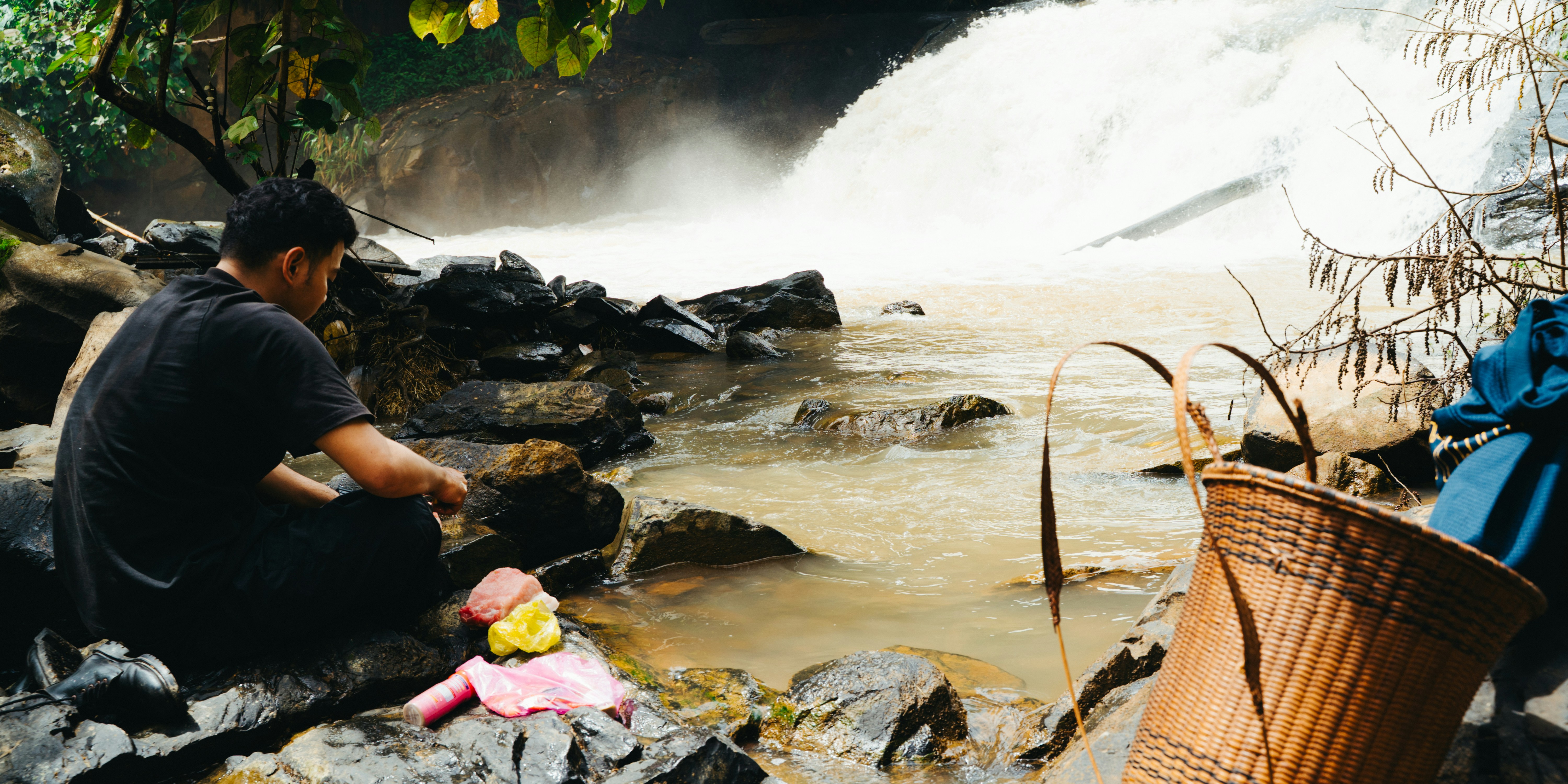Contemplation at the River's Edge: A Solitary Figure Beside a Roaring Falls