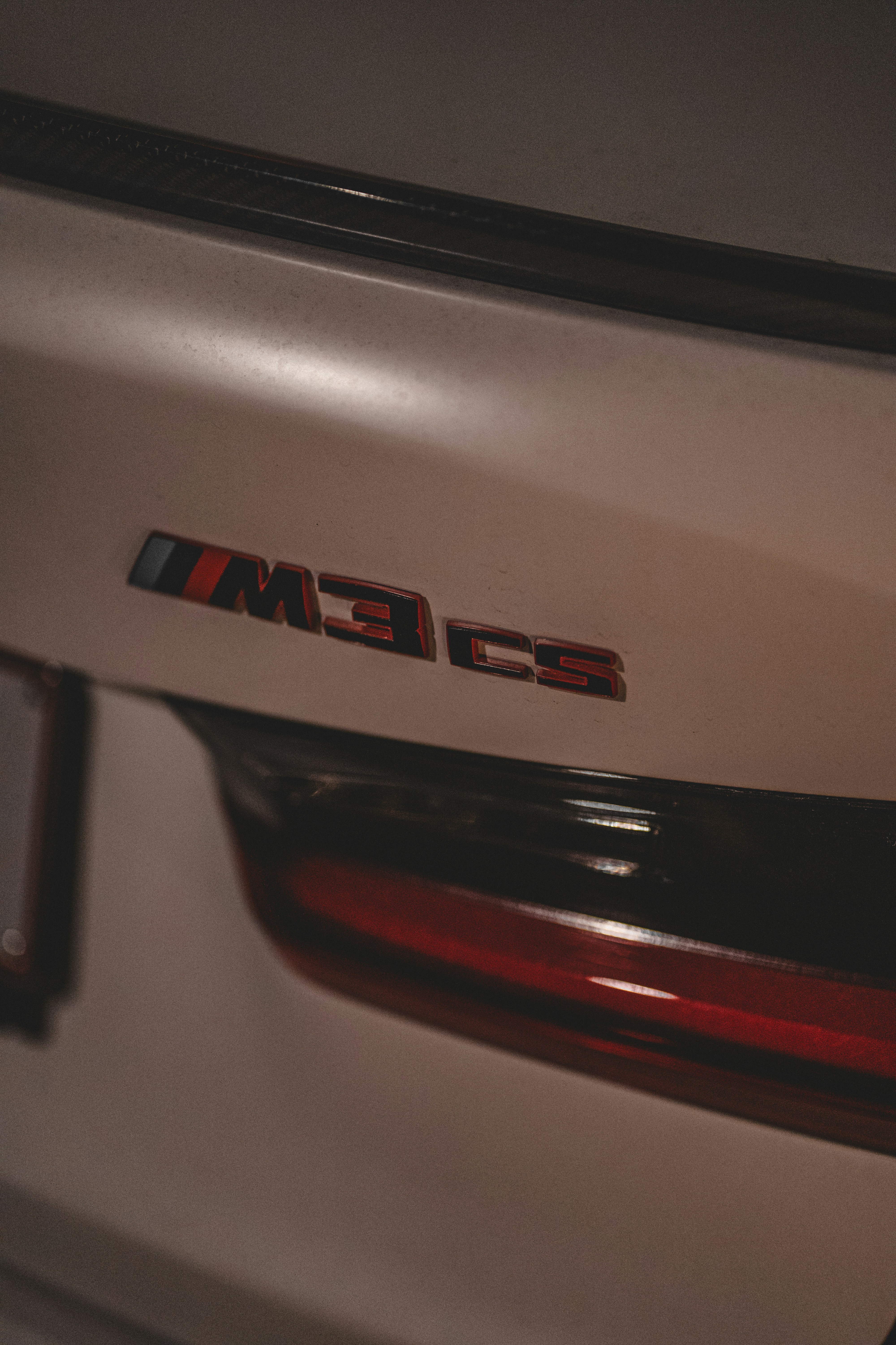 Moody Close-Up of a Car Badge Drenched in Dim Taillight Glow