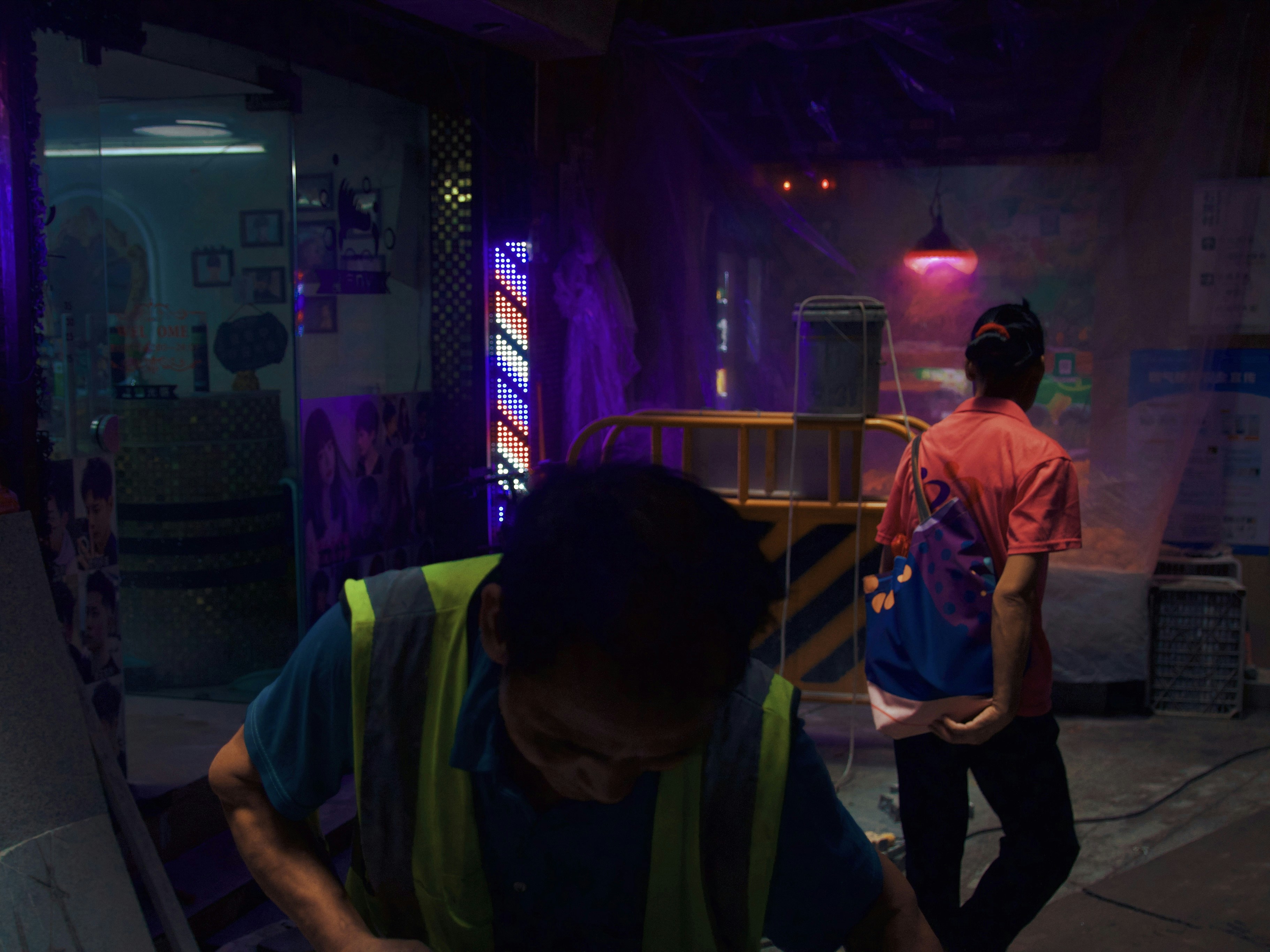 Neon Veil in a Dim Industrial Backroom: Two Crew Members at Work