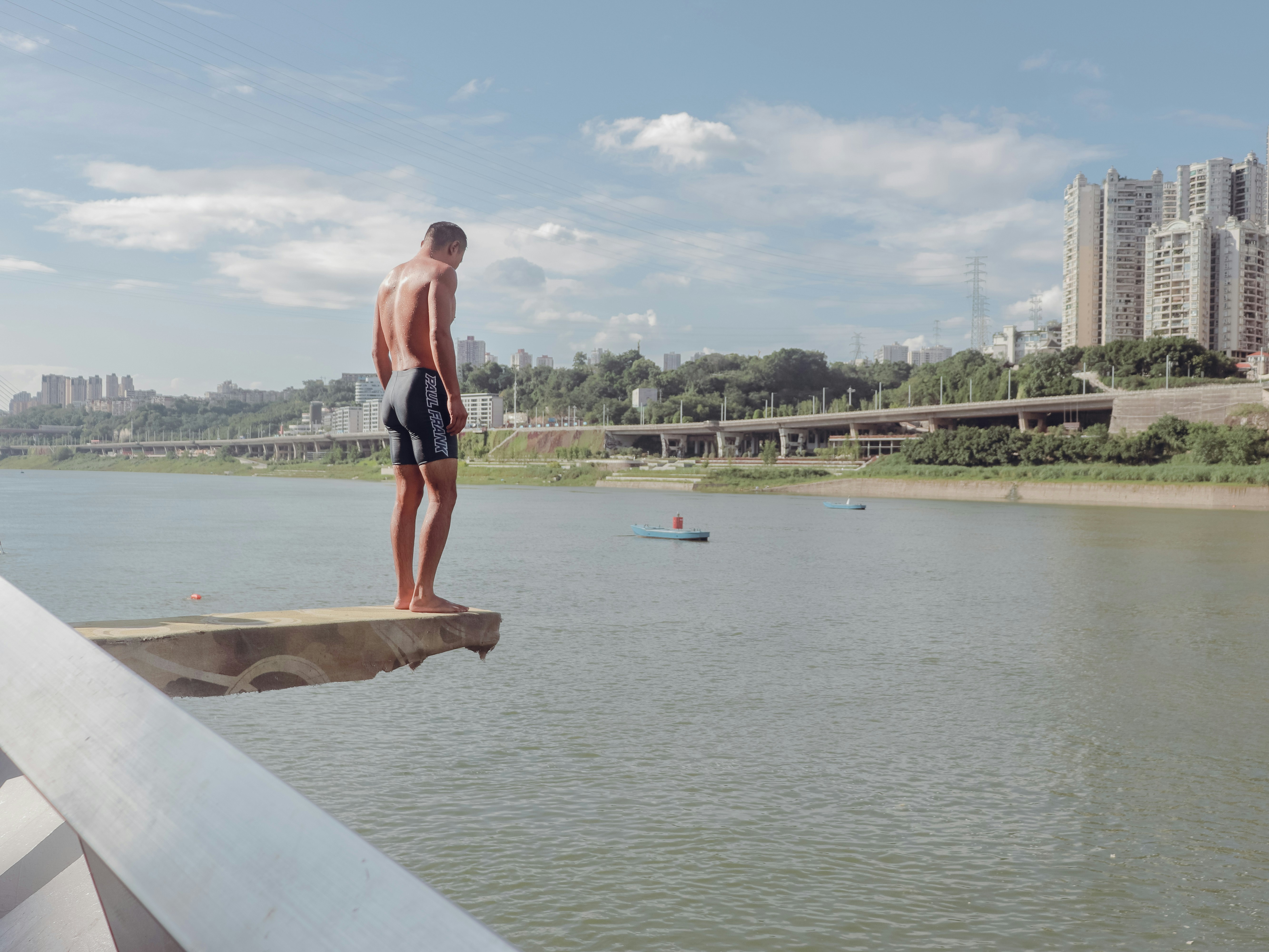 On the Brink: A Lone Diver Poised Over Riverside Stillness