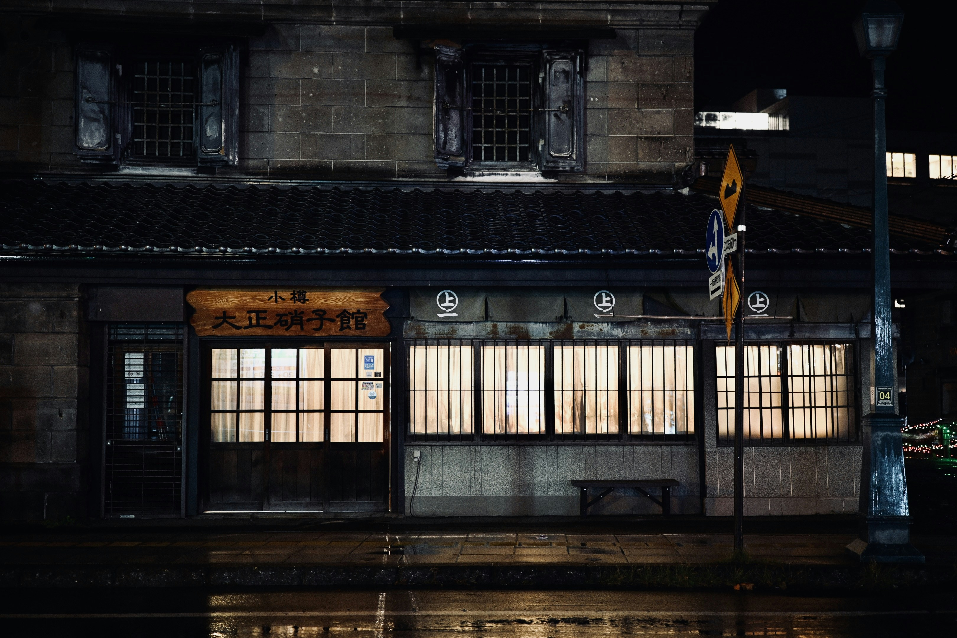 Warm Window Light Through a Historic Storefront on a Rain-Washed Night
