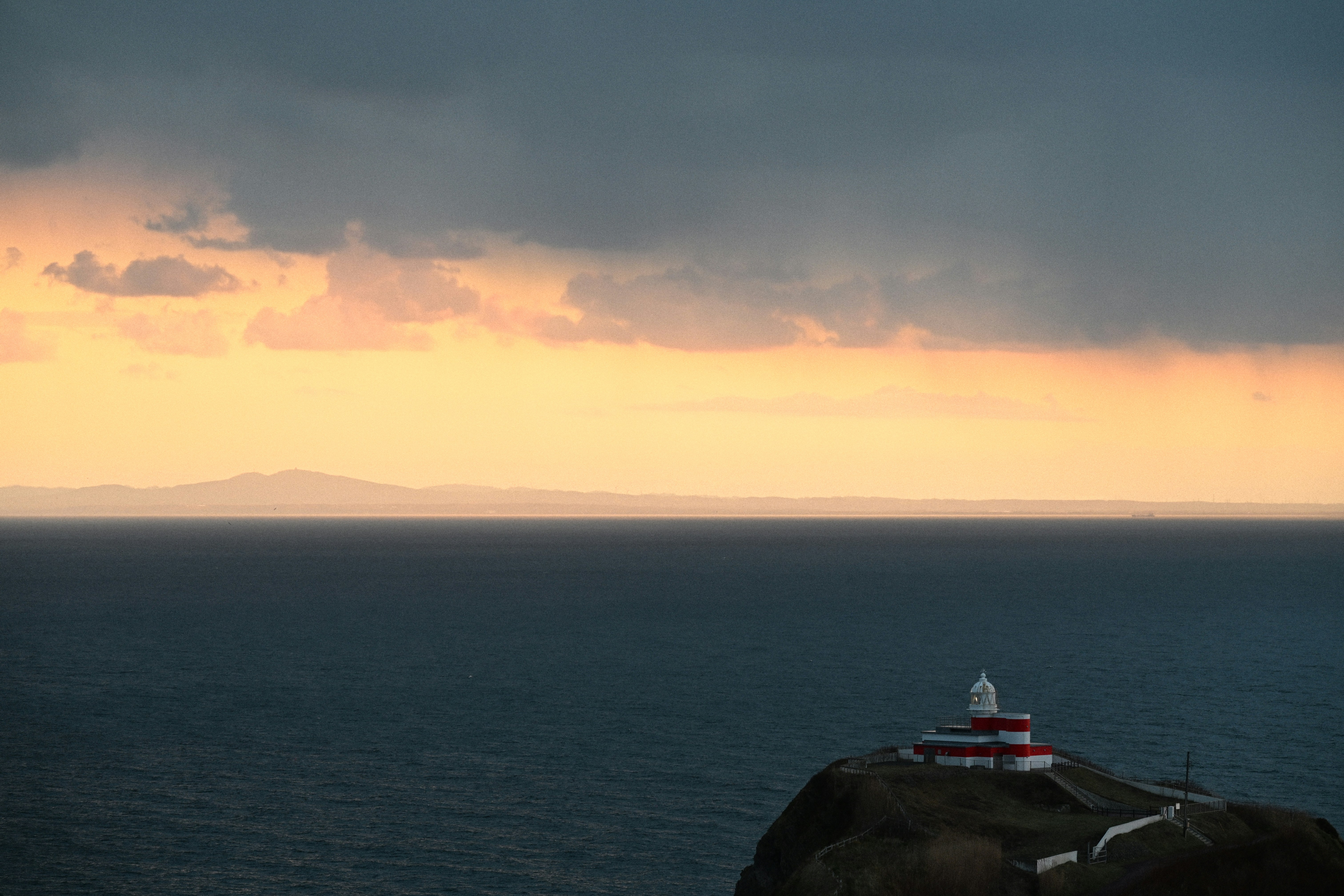 Red Beacon at the Edge: Dusk Light Over a Quiet Sea Cliff