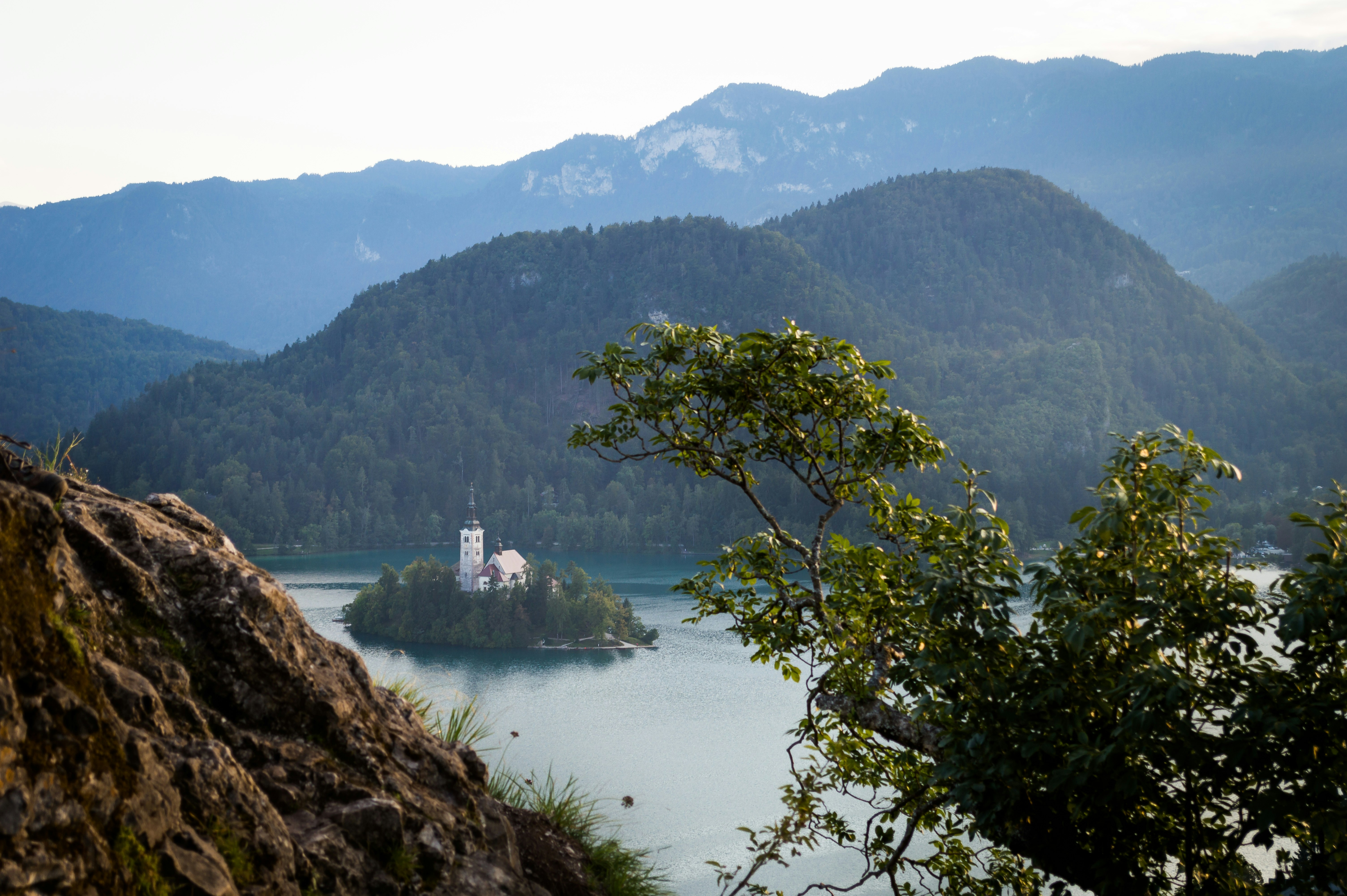 Isolated Chapel on a Tranquil Alpine Lake, Framed by Pine-Studded Ridges