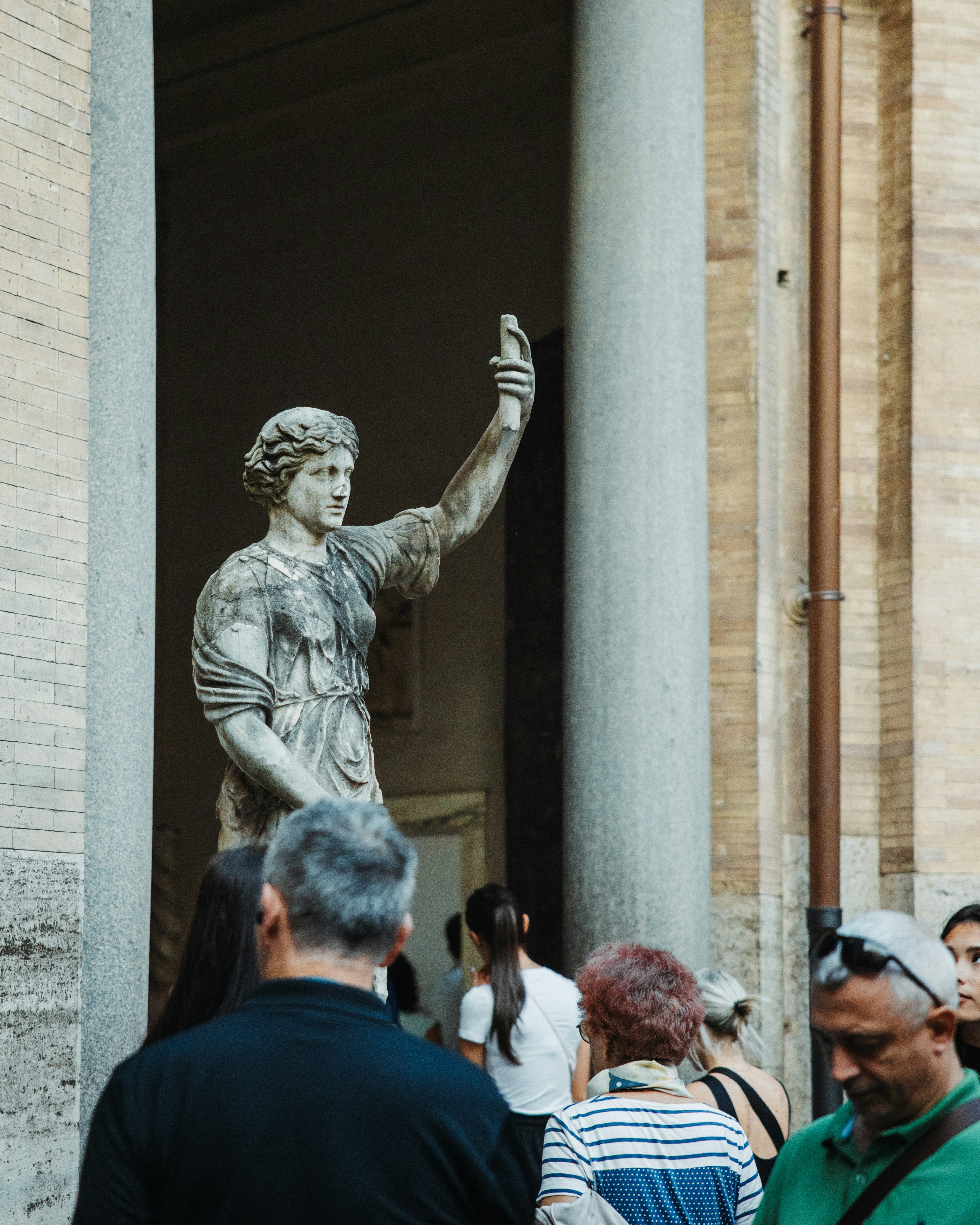 Doorway Echoes: A marble statue framed by a living crowd