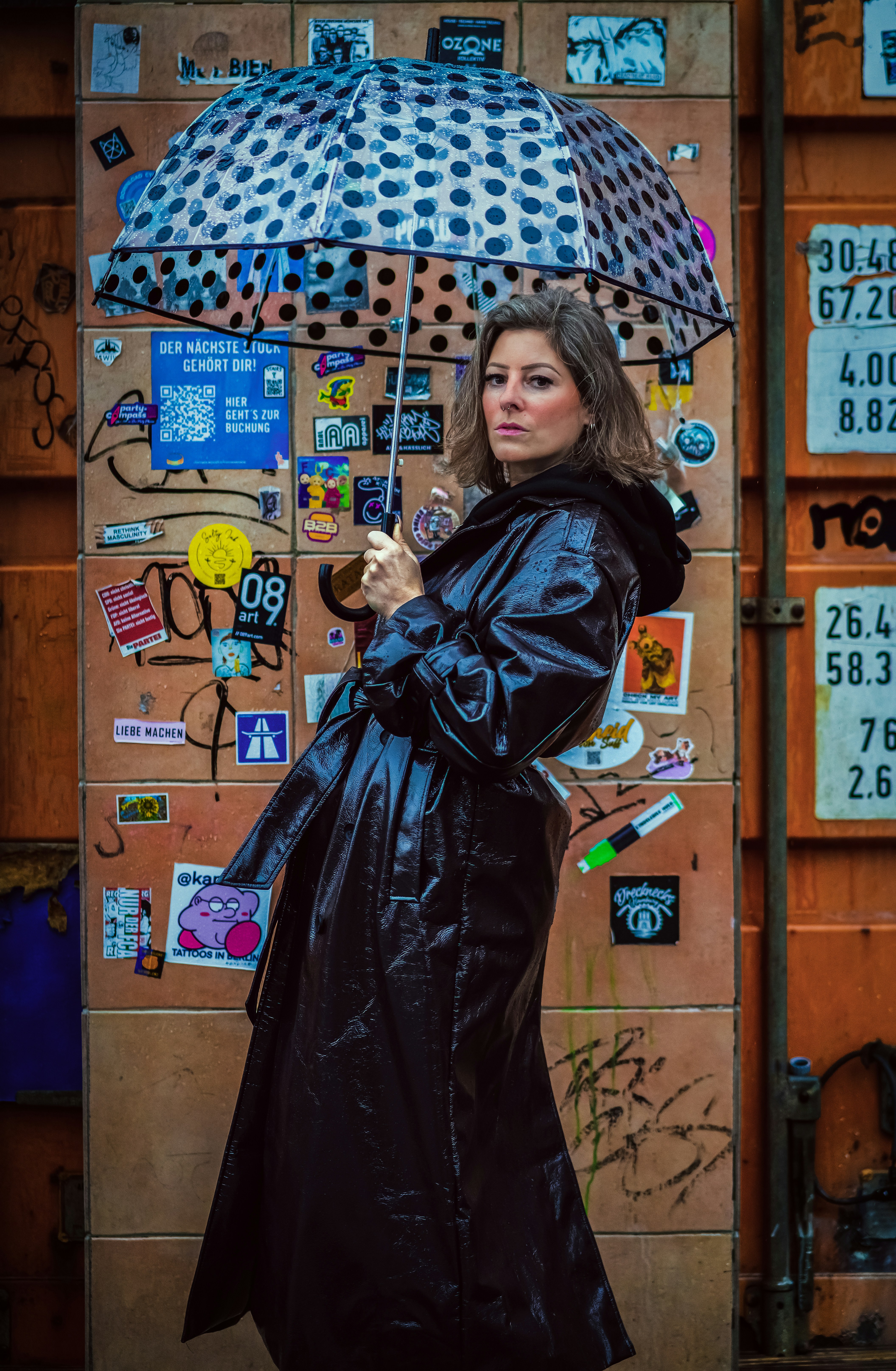 Polka-Dot Umbrella, Stickered Backdrop: A Rain-Kissed Street Portrait