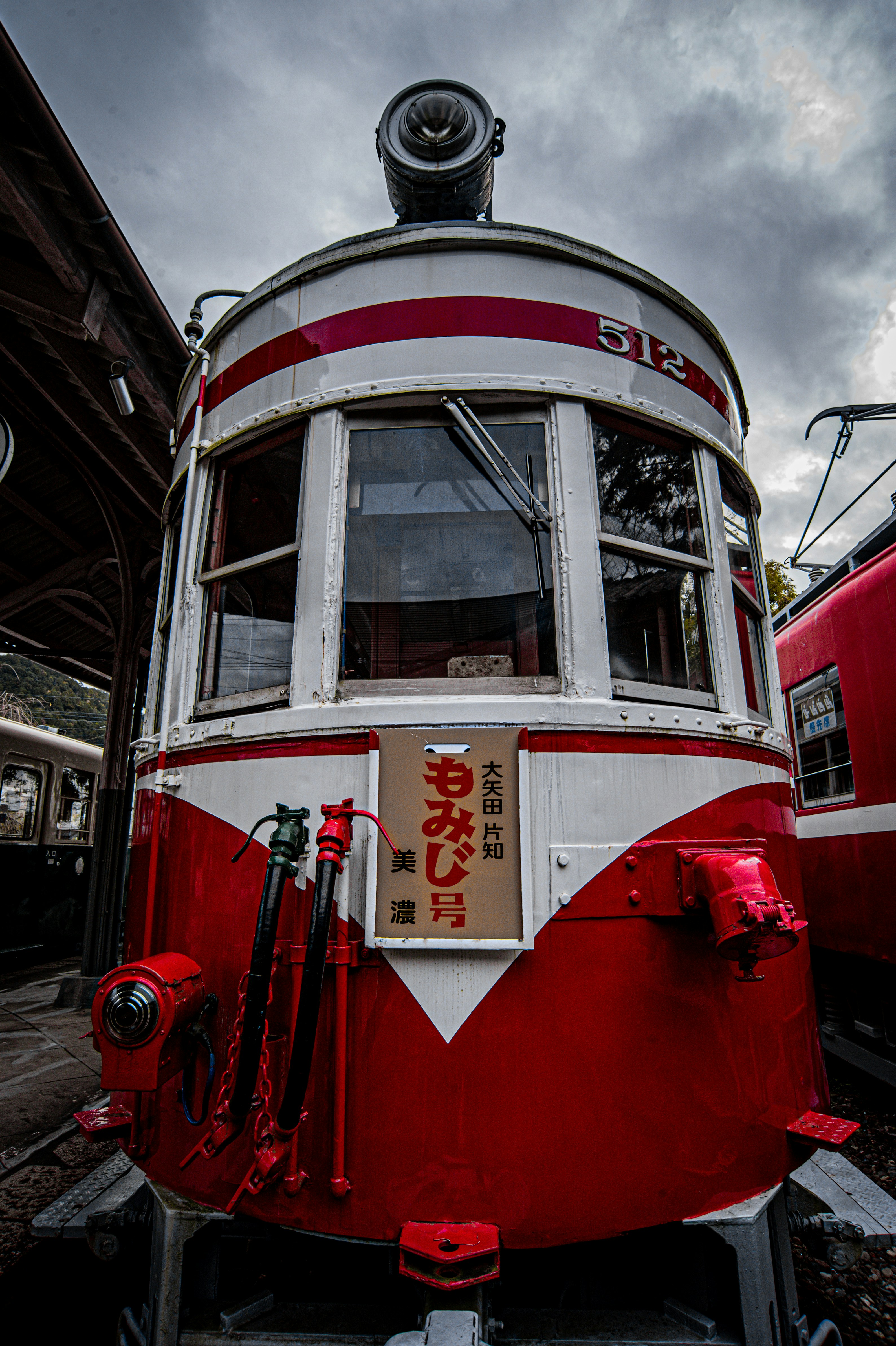 Crimson Cabfront: A Vintage Tram Framed by Cloudy Skies