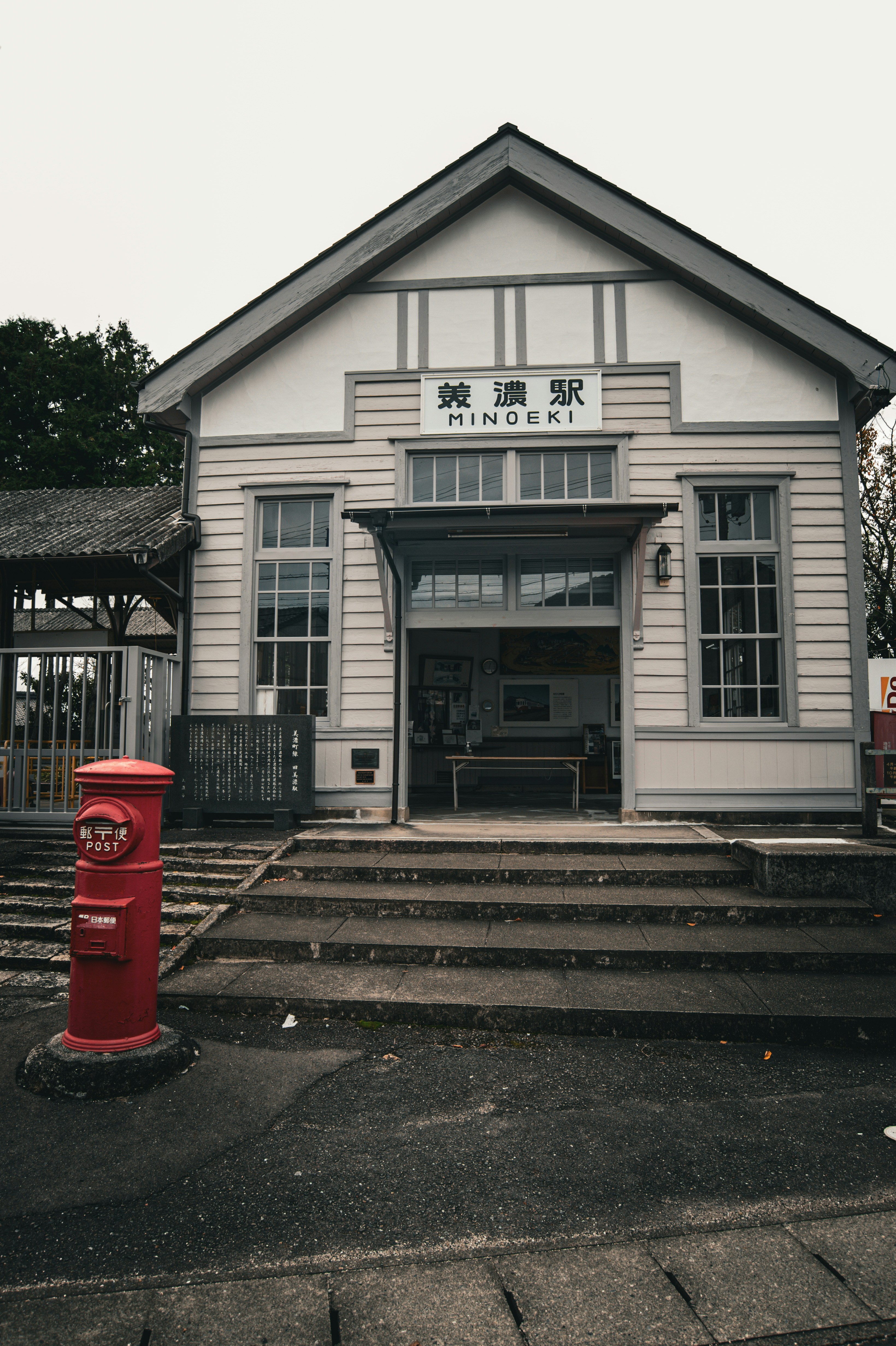 Minoeki Station: A Vintage Japanese Rail Stop Framed by a Bold Red Post