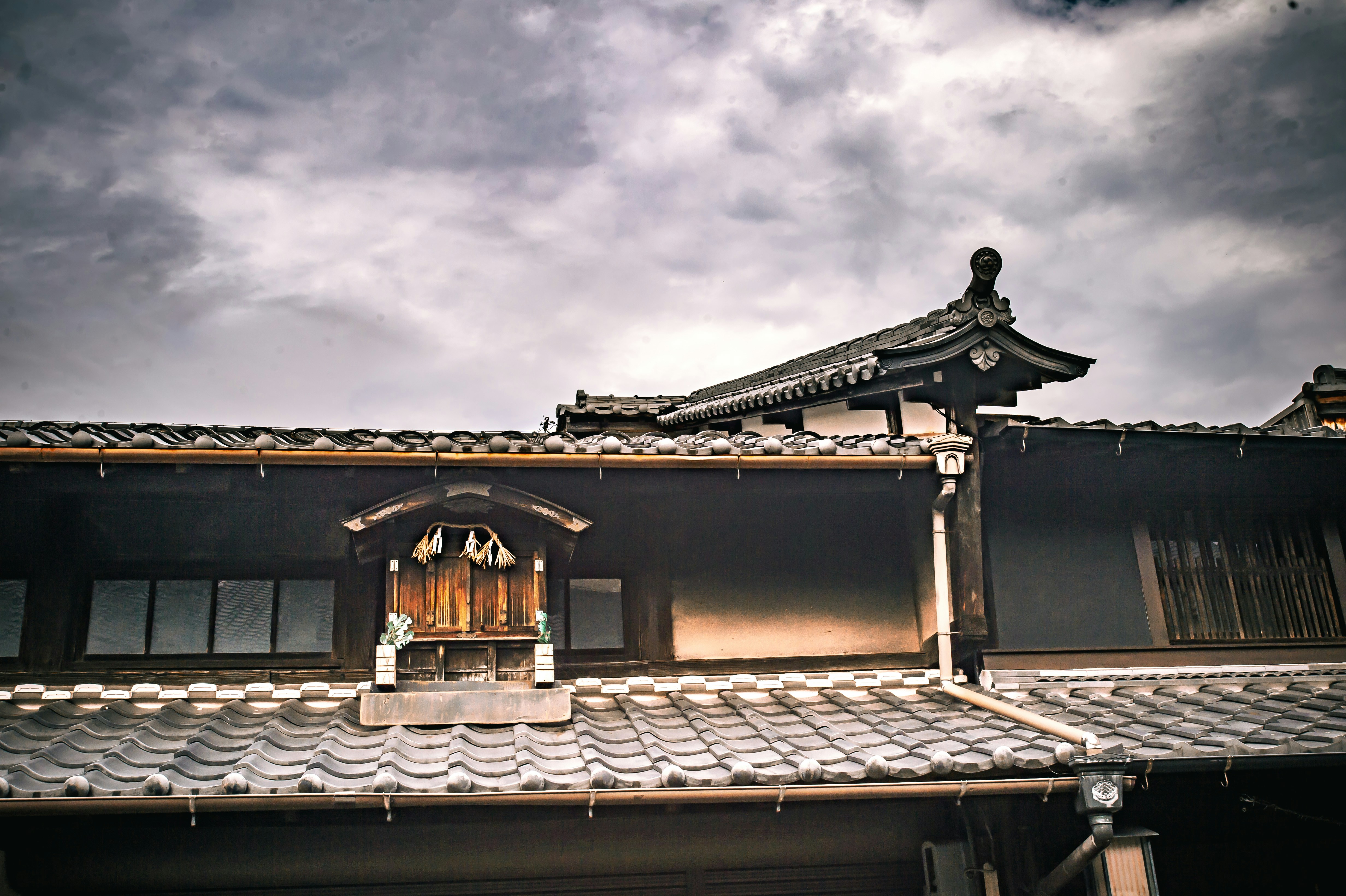 Eaves of Quiet Craft: A Japanese Tile Roof Framed by Moody Skies