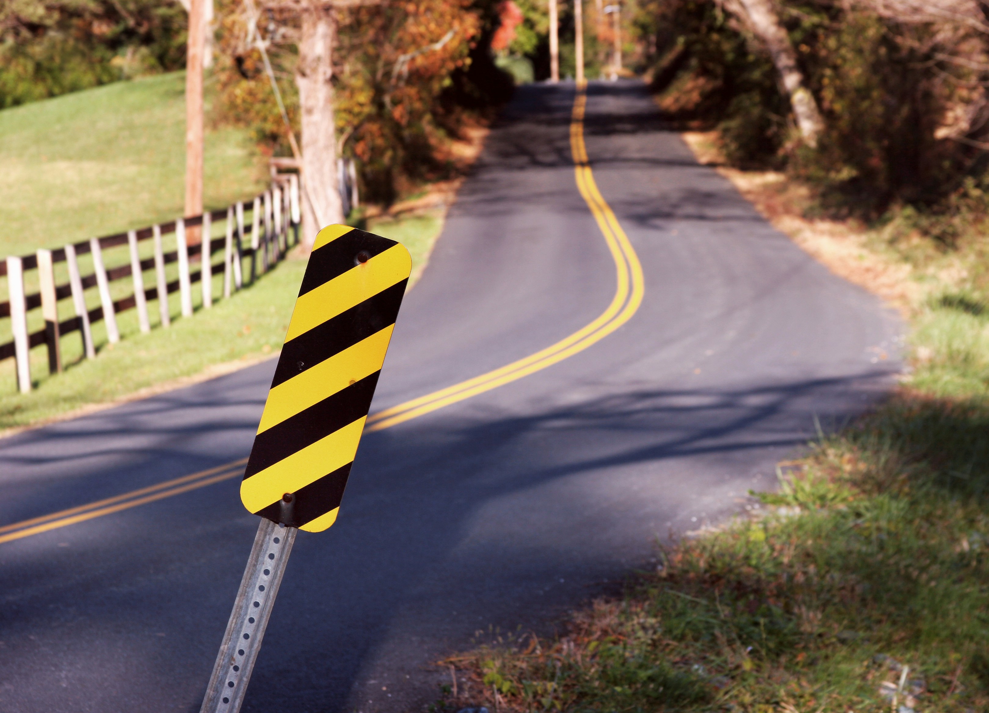 The Quiet Bend: Striped Hazard Sign Guards a Winding Country Road
