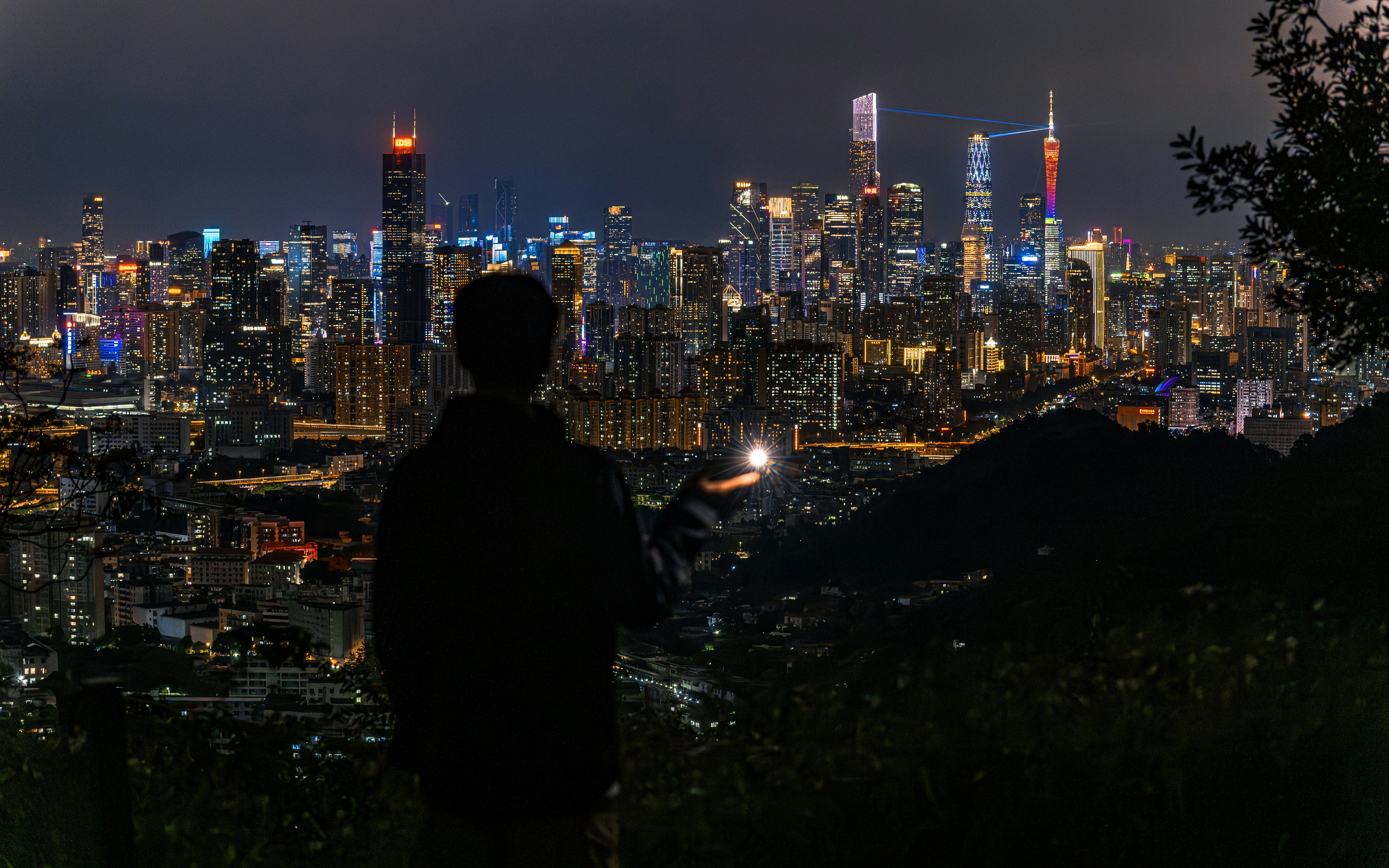 Silhouette on the Ridge as Neon Skyline Unfolds at Night