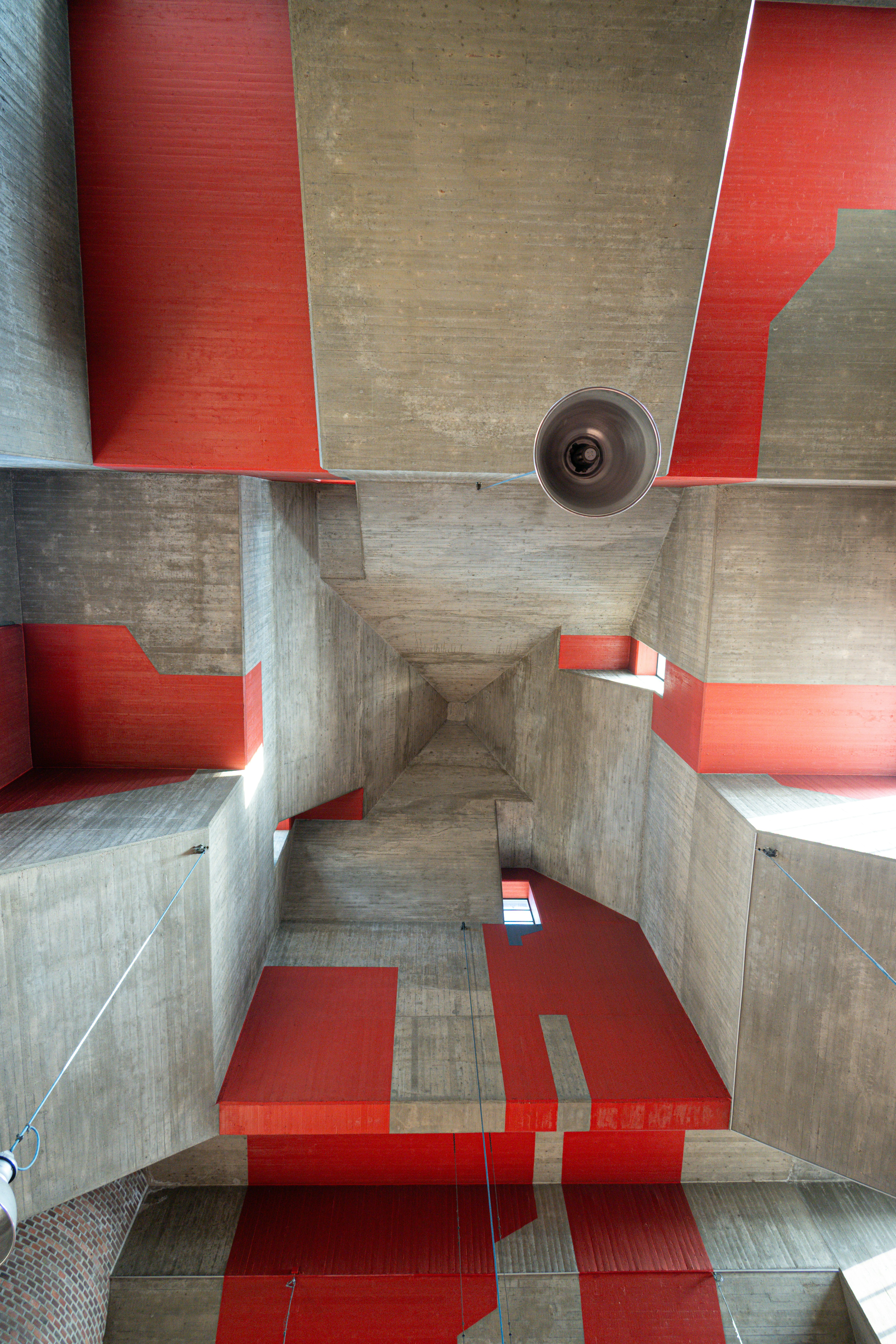 Red Angles Ascend: Concrete Atrium Geometry Framing a Central Light