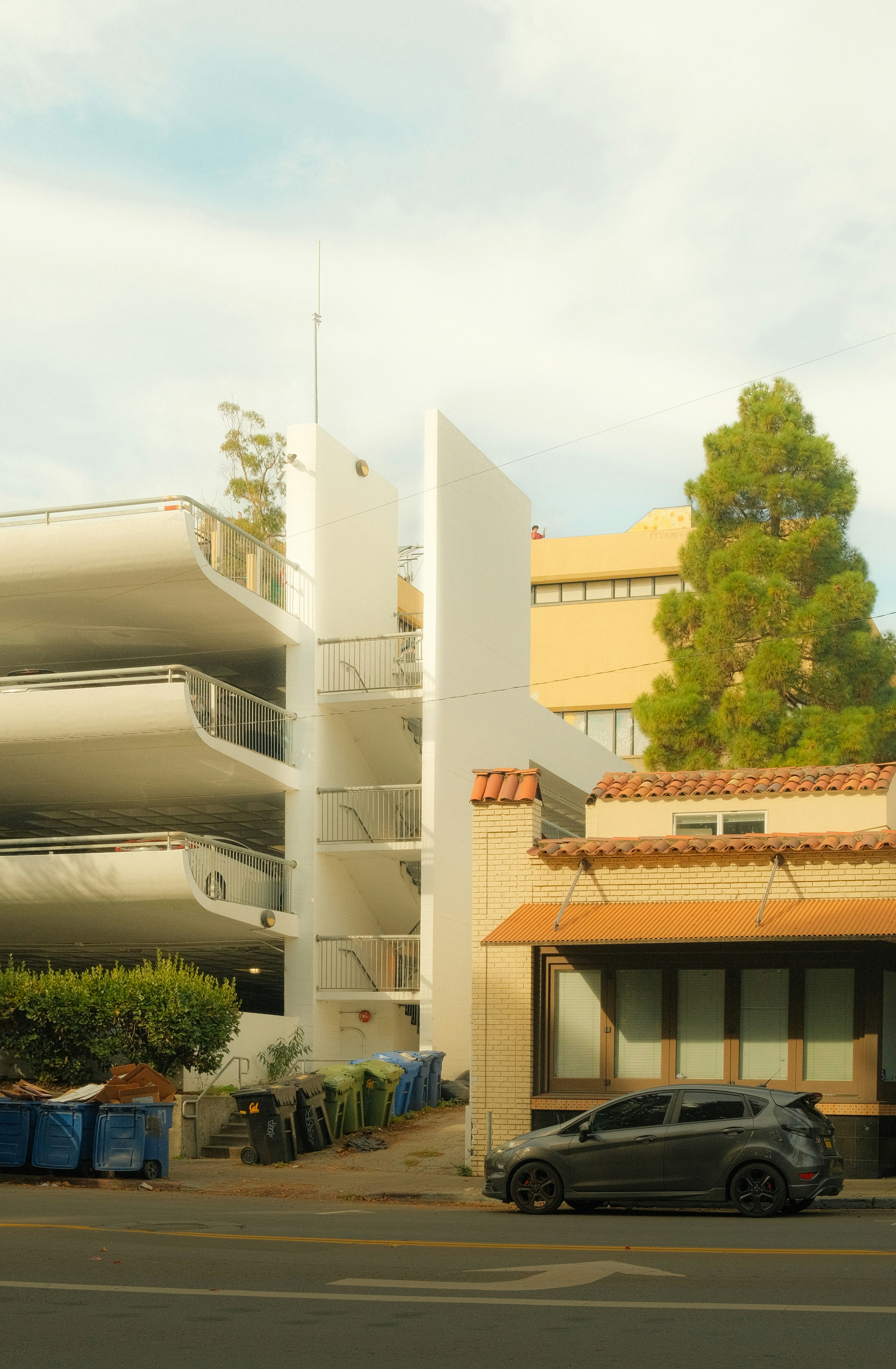 Geometry in Sunlight: White Parking Structure Framed by a Red-Tiled Streetfront