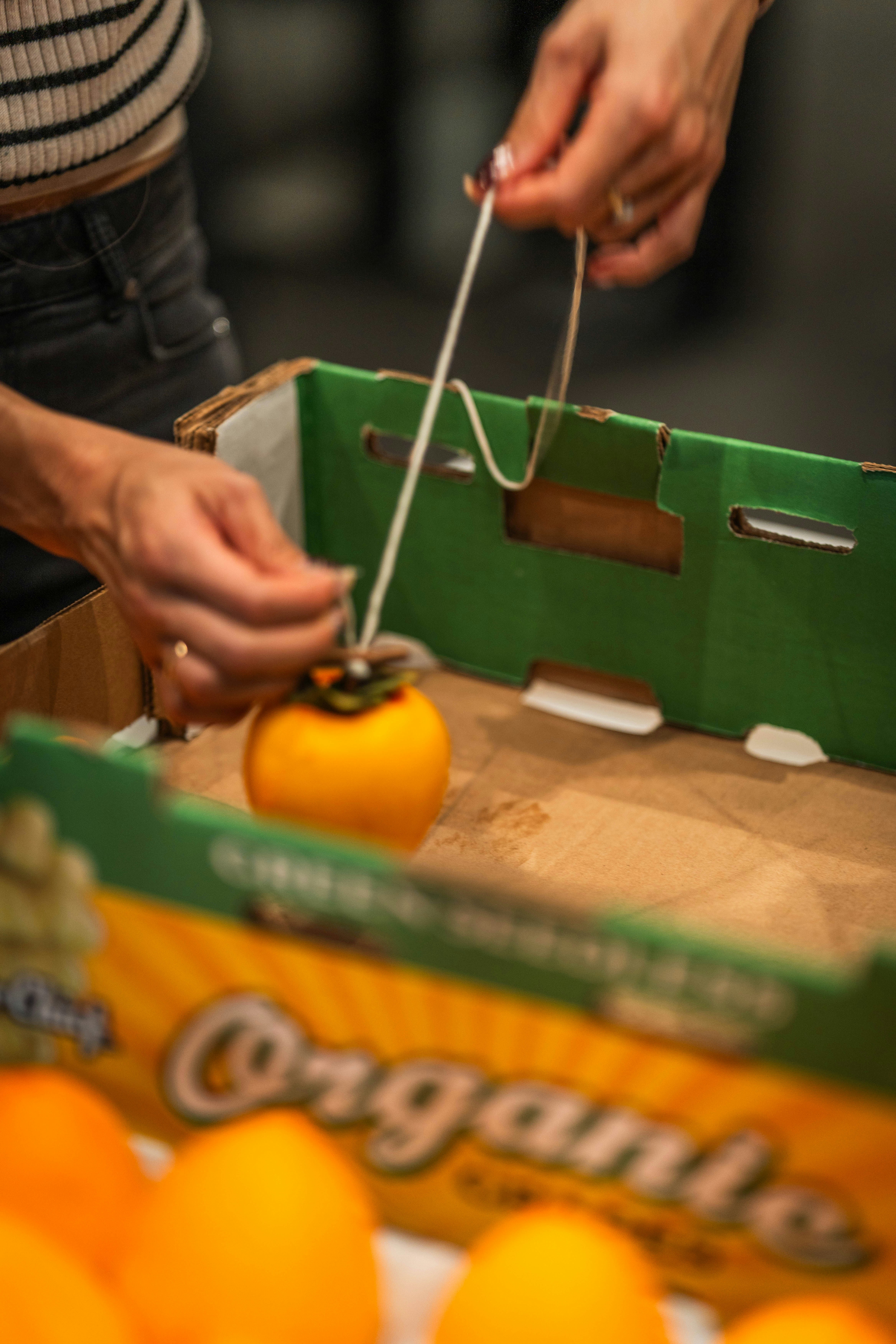 Tying a Citrus Charm: A Hands-On Moment in a Market Crate