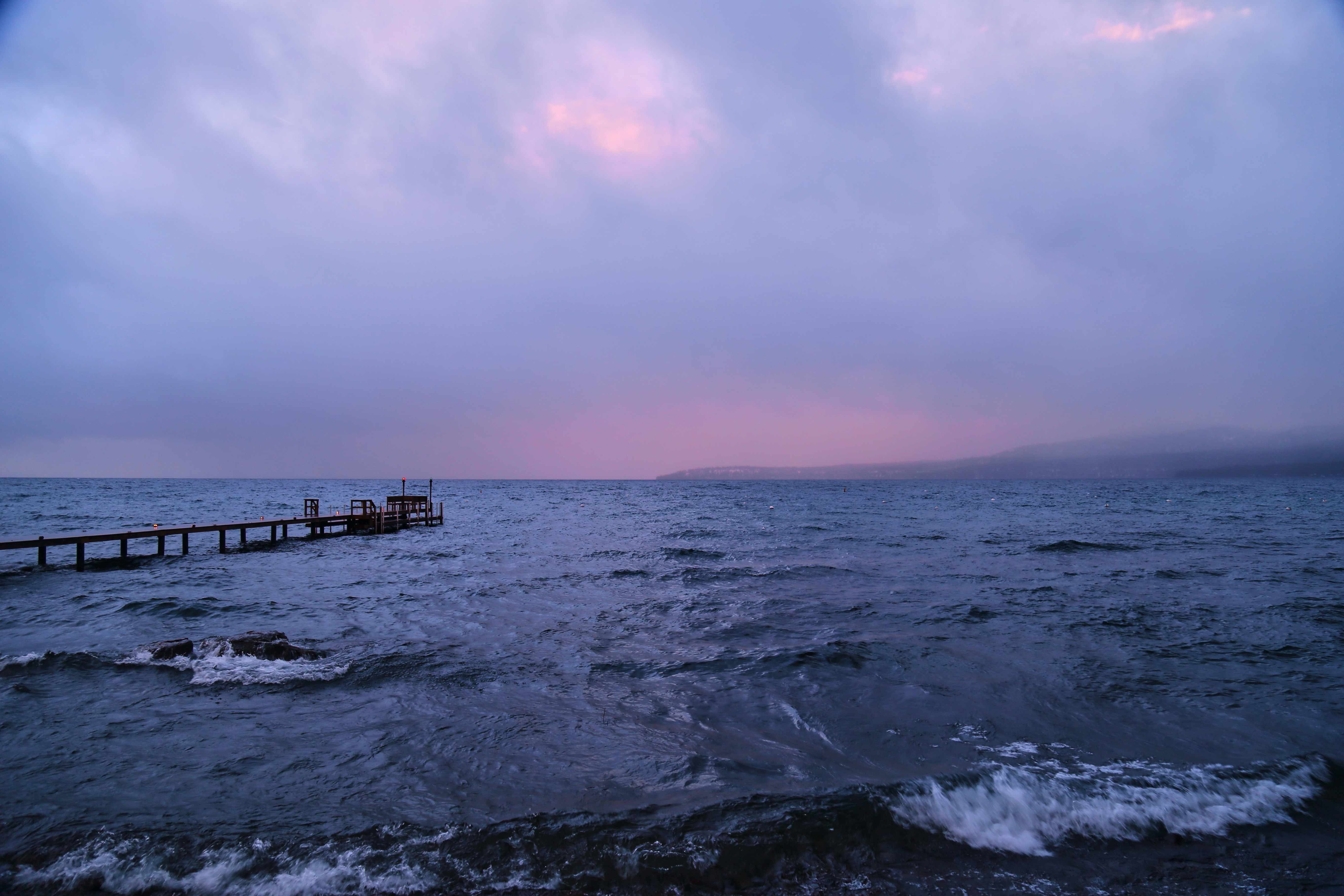 Horizon Glow Beyond the Pier: Dusk Over a Churning Sea