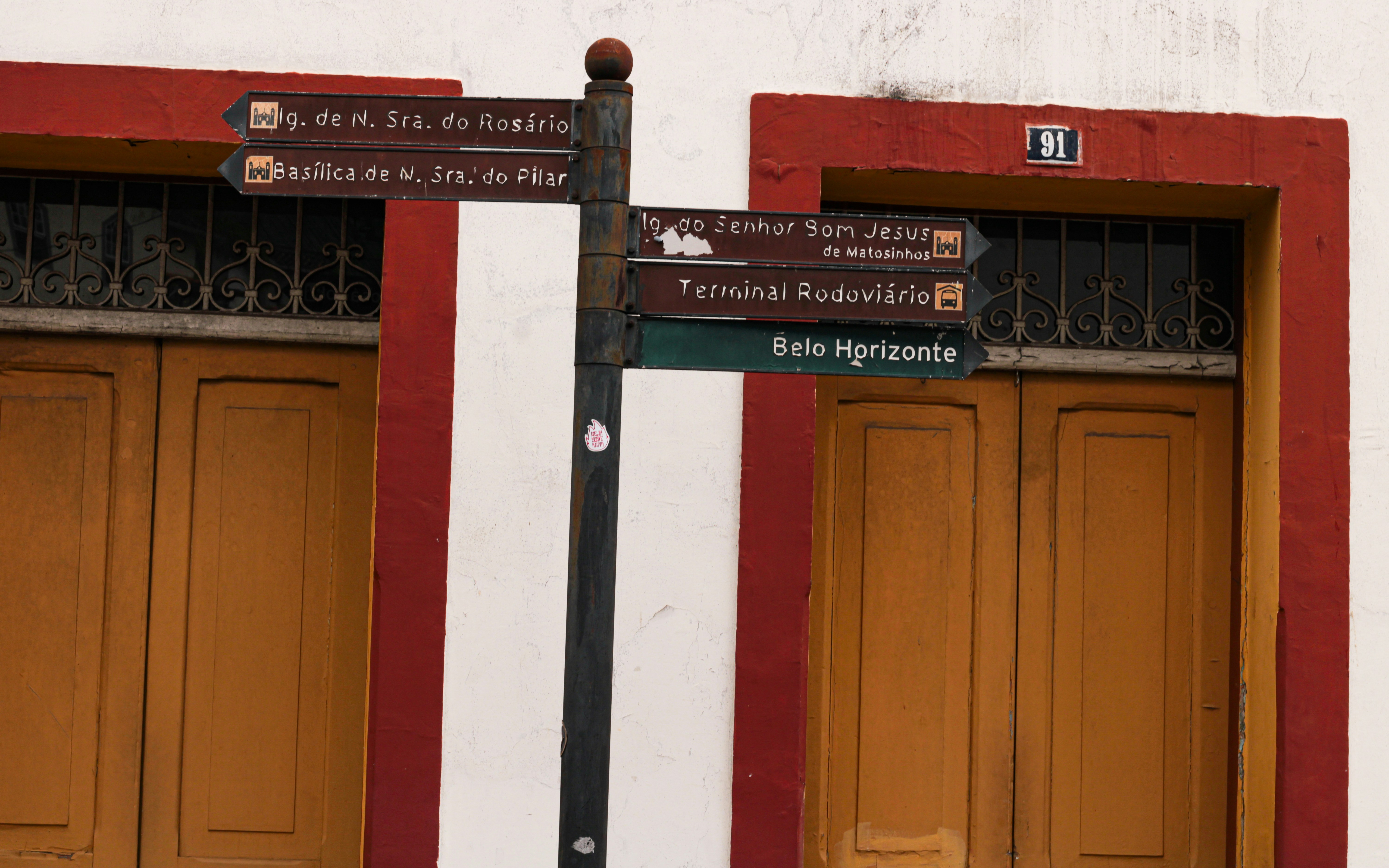 Directional Signpost Framed by Coral Doors and Red Trim