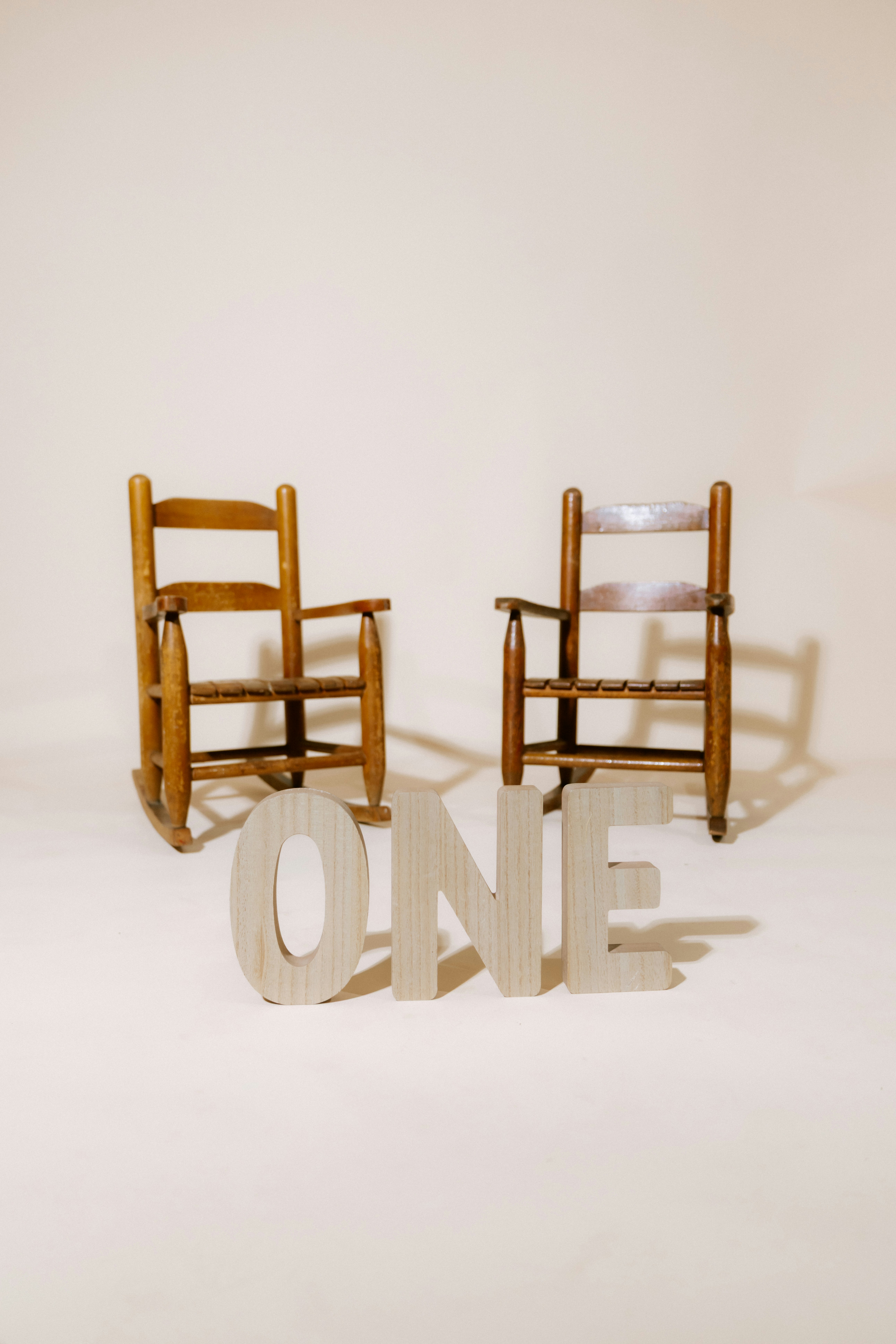 Two Rustic Rocking Chairs Guard the Word ONE in Soft Studio Light