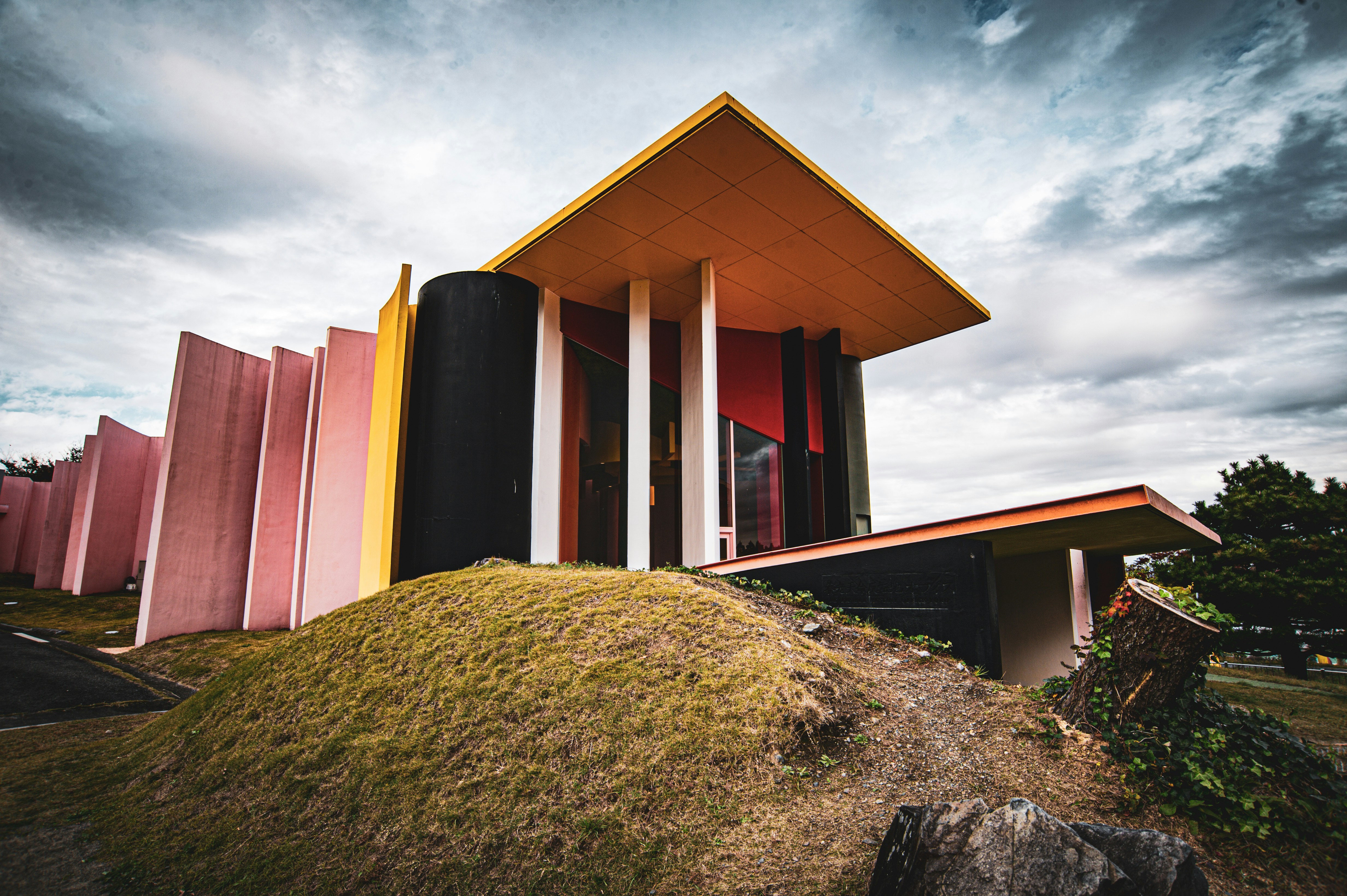 Prismatic Pavilion Rising from a Grassy Knoll Beneath a Dramatic Sky
