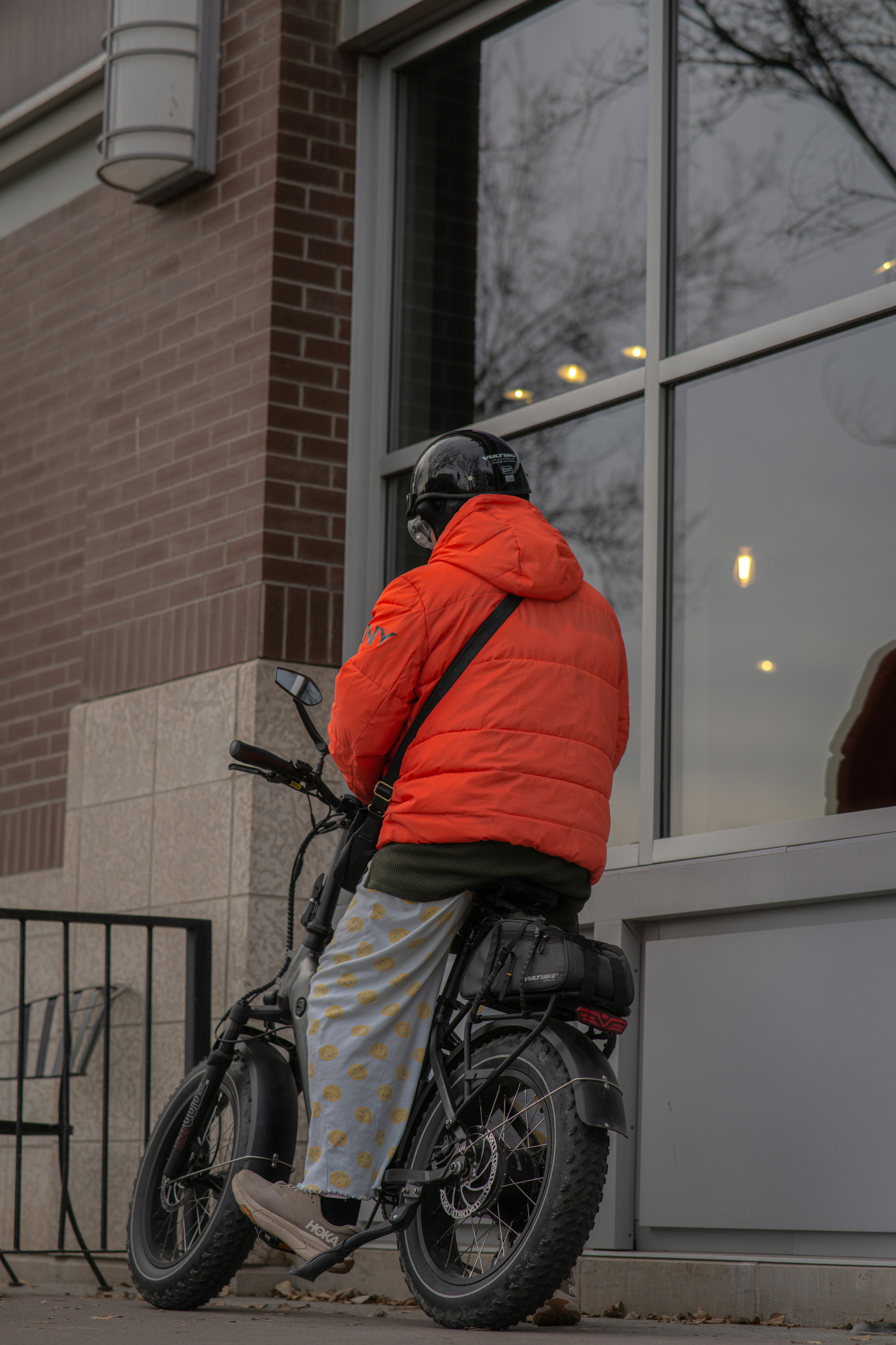 Orange Beacon by Brick-and-Glass: A City Cyclist Pauses at the Storefront