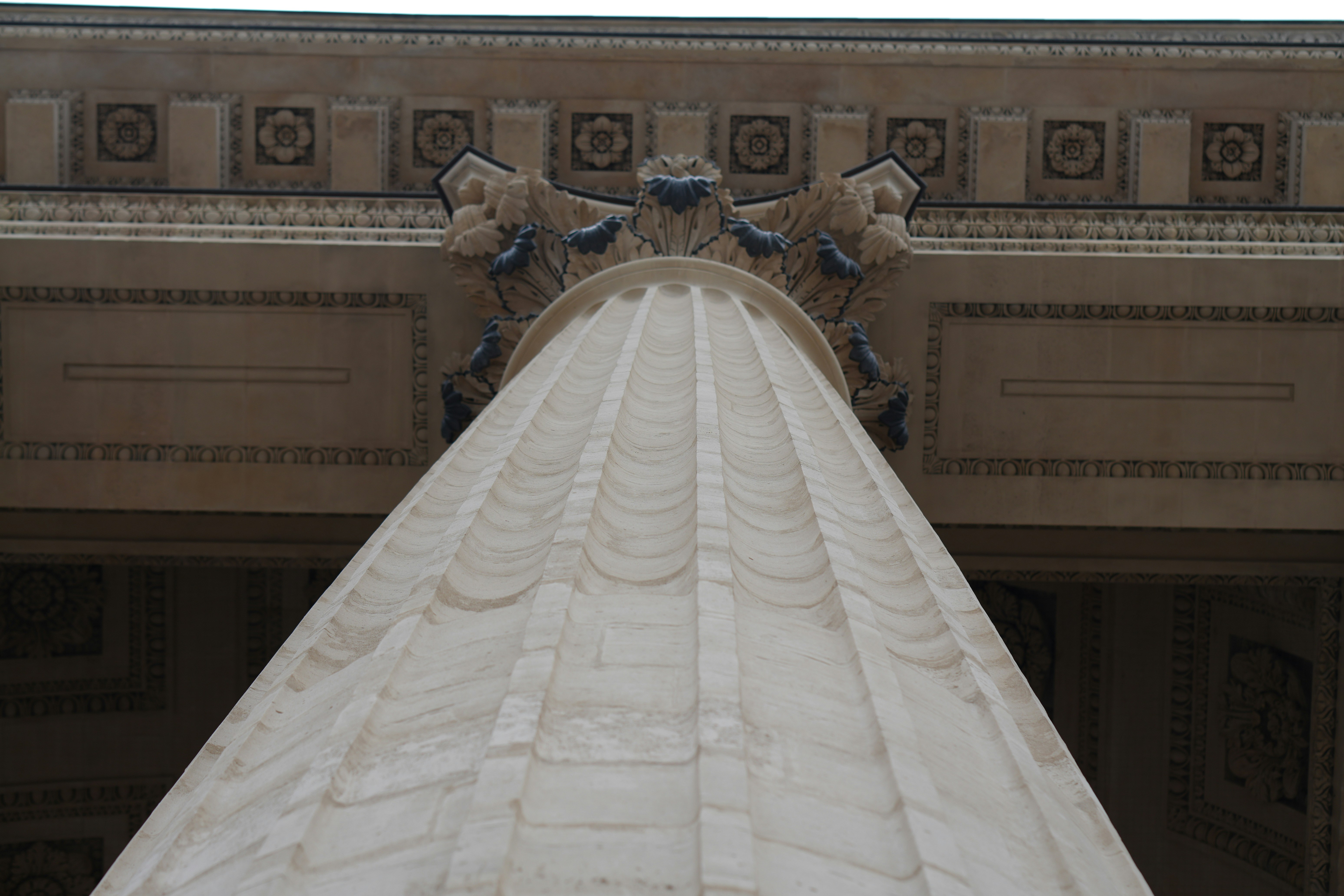 Rising Monument: A Low-Angle Portrait of a Fluted Column Beneath Ornamented Entablature