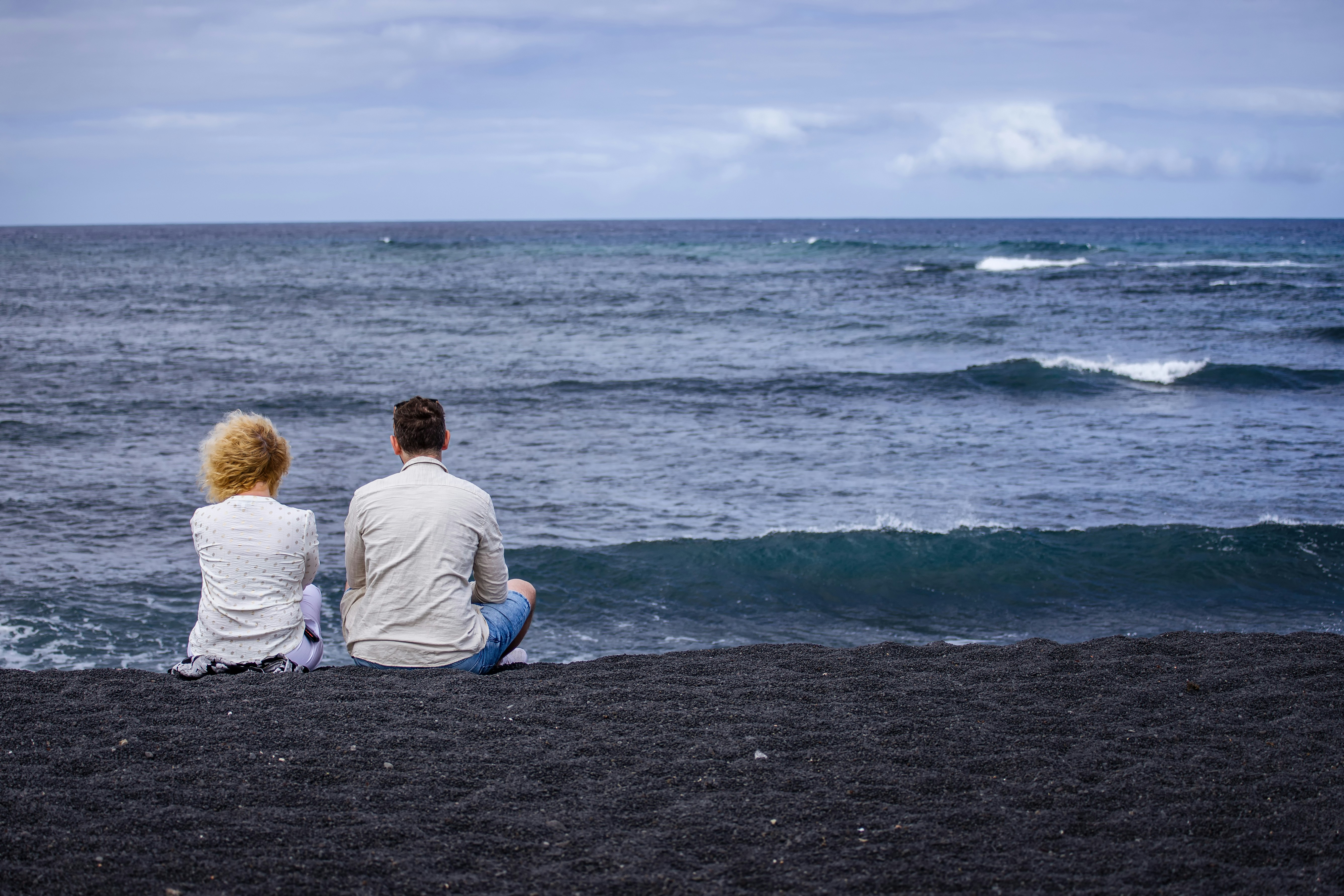 Quiet Pair on Black Sand: A Seaside Moment Watching the Ocean