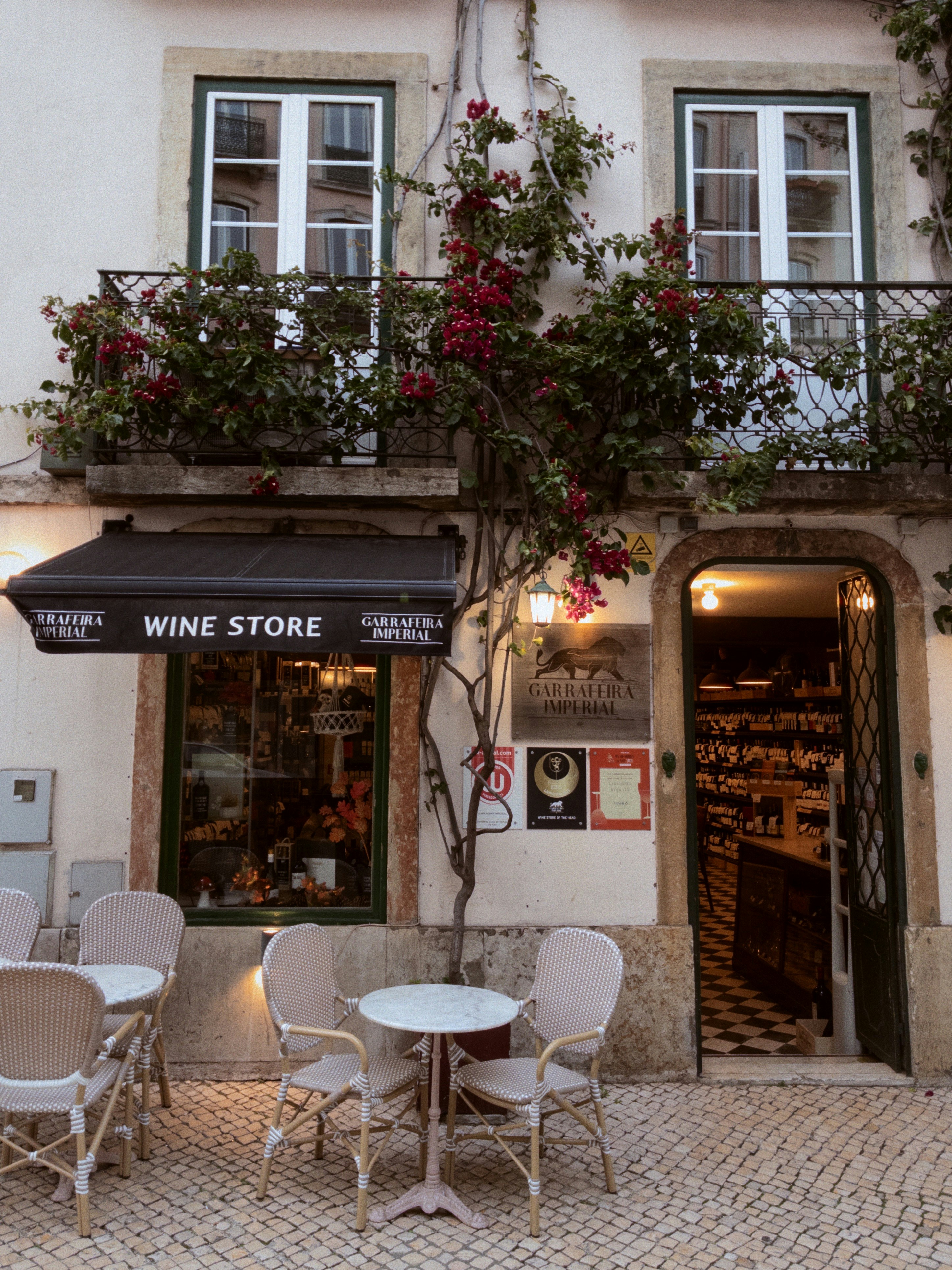 Wine store with outdoor seating and flowering vines.