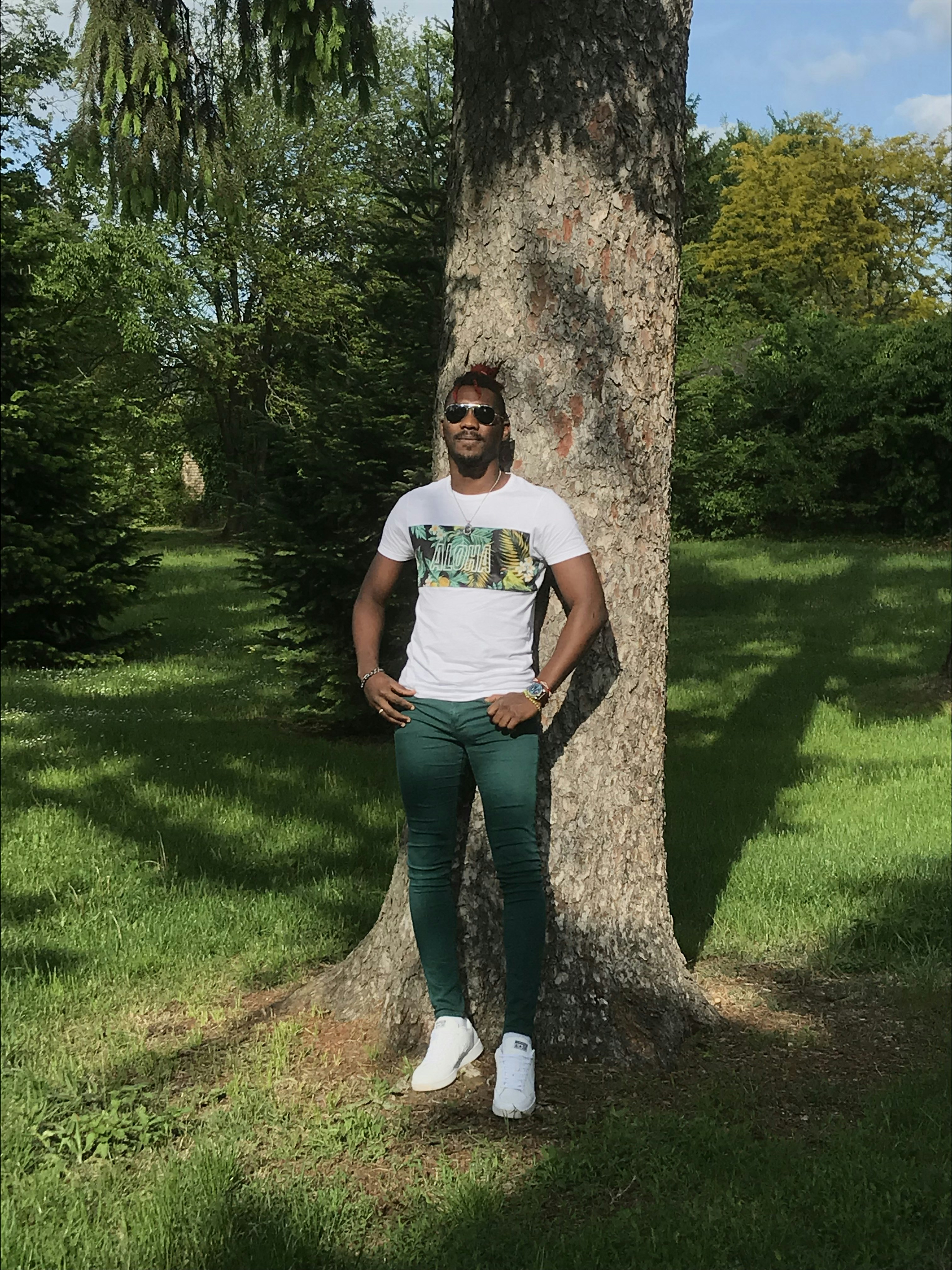 man standing by tree in a park in sunlight