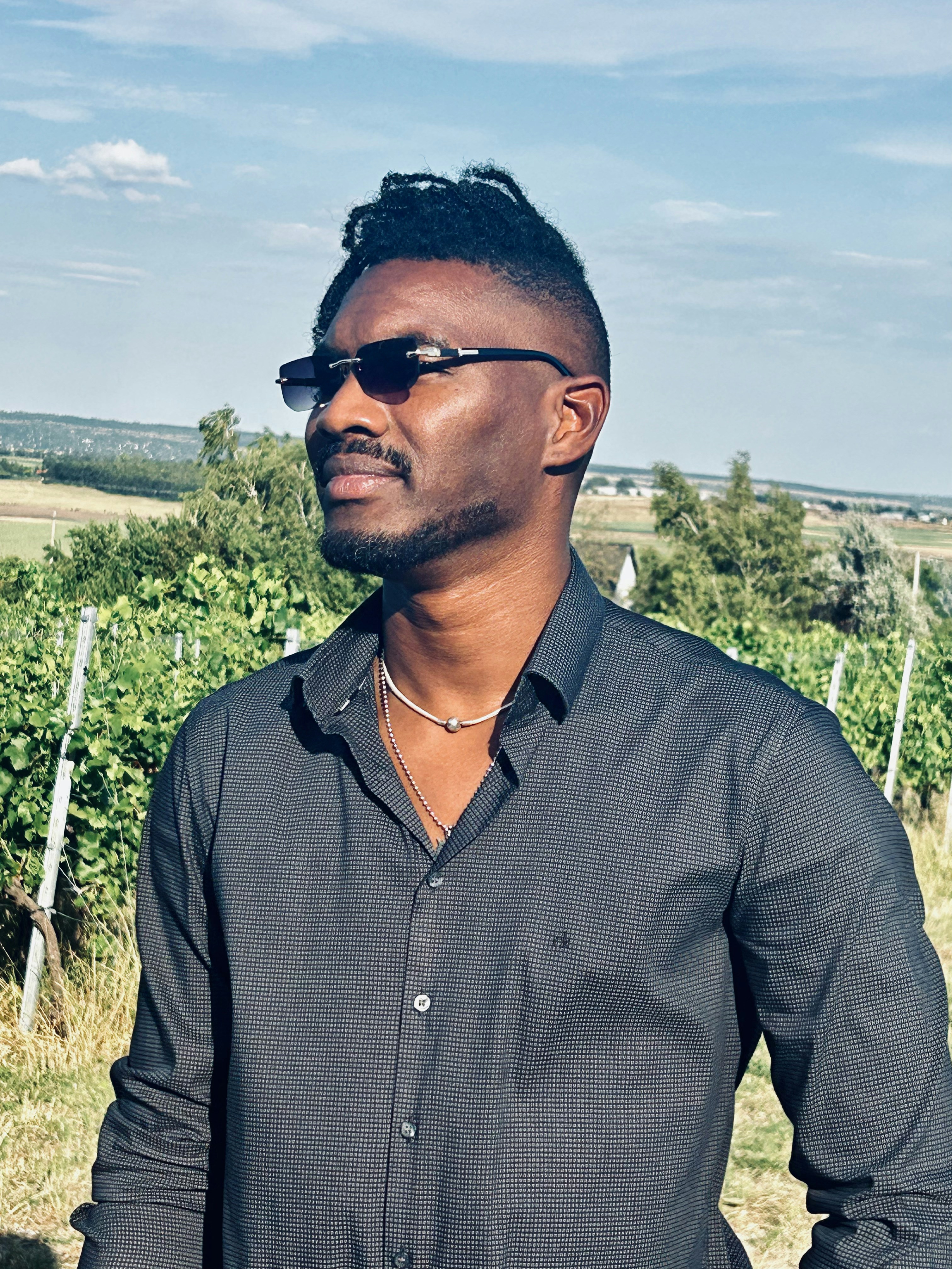 Sunglasses at Noon: A Quiet Portrait Among Sunlit Vines