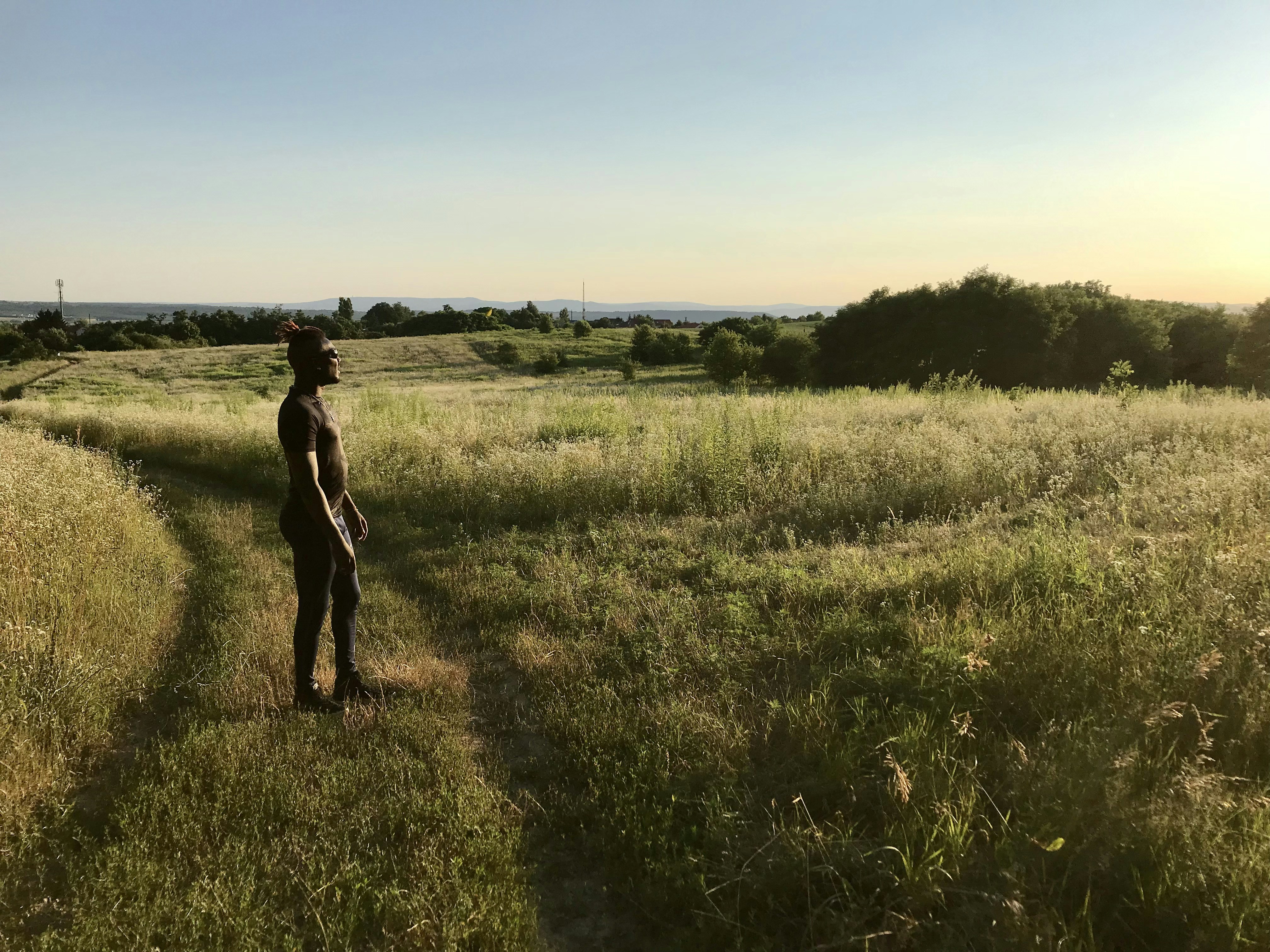 man standing on green hill countryside