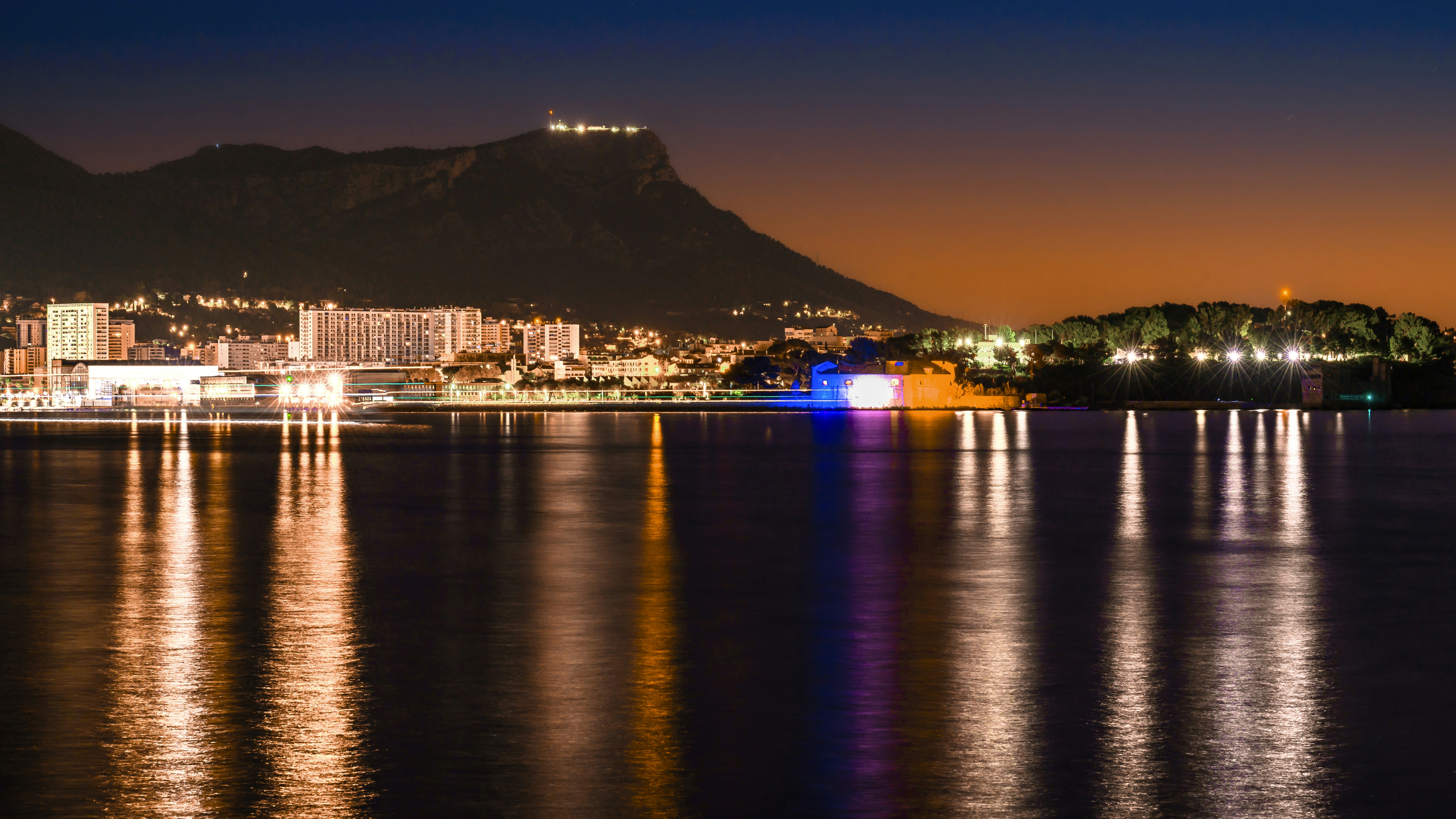 Twilight Reflections: Neon Trails Across a Quiet Waterfront