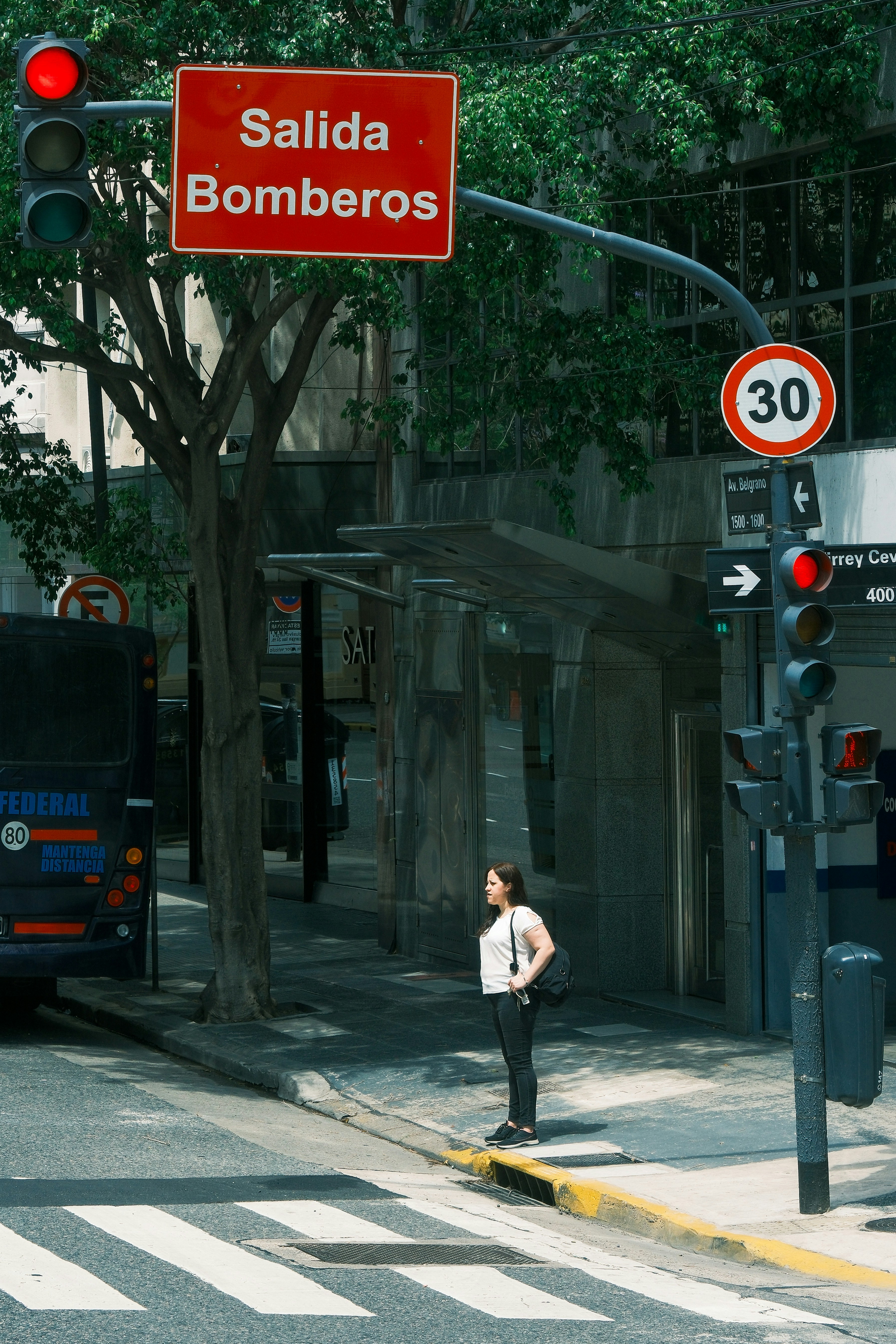 Salida Bomberos Moment: A lone pedestrian at a sunlit city crosswalk
