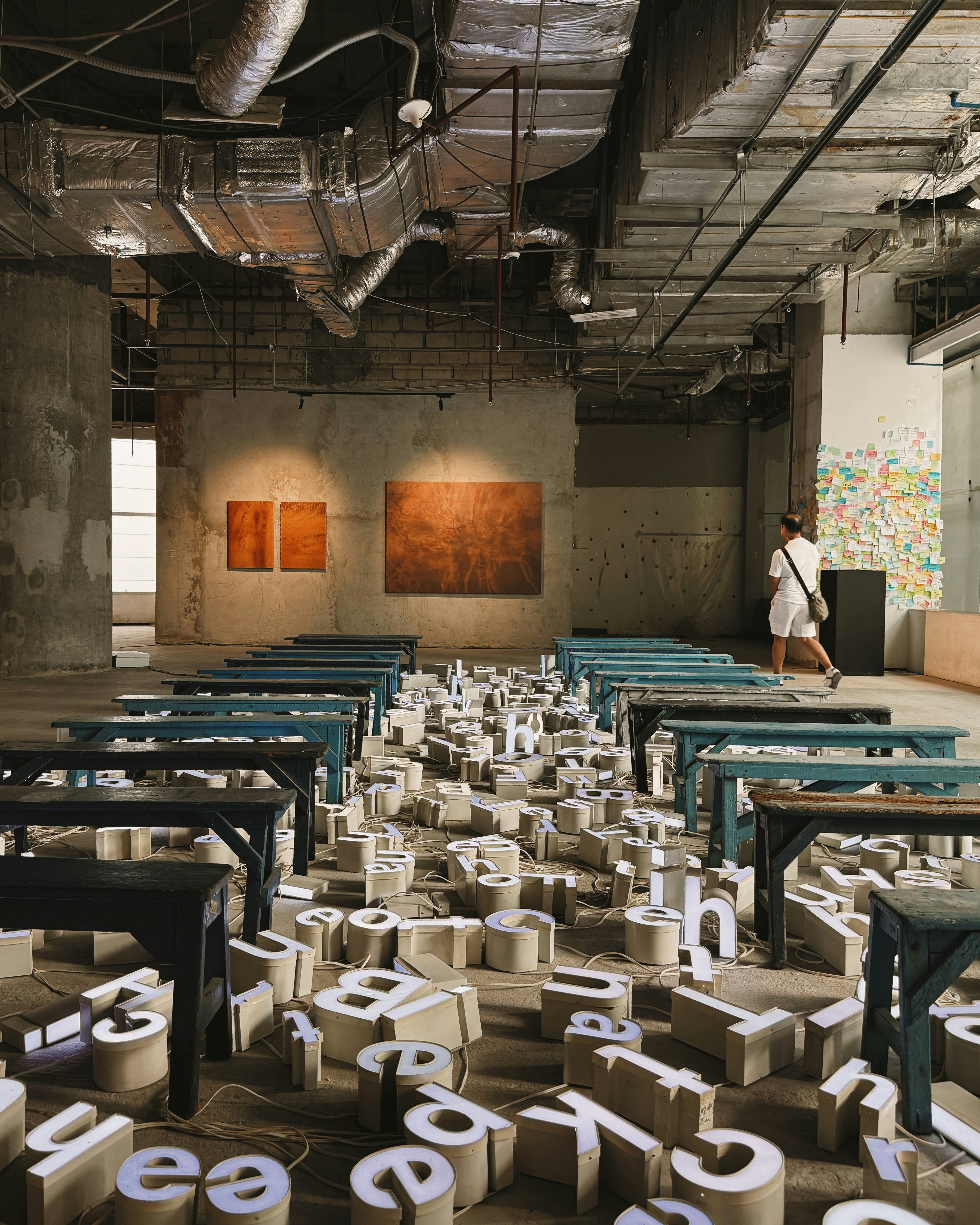 Typography Spill in an Industrial Gallery: Letters on the Floor Converge Toward an Ember-Orange Back Wall