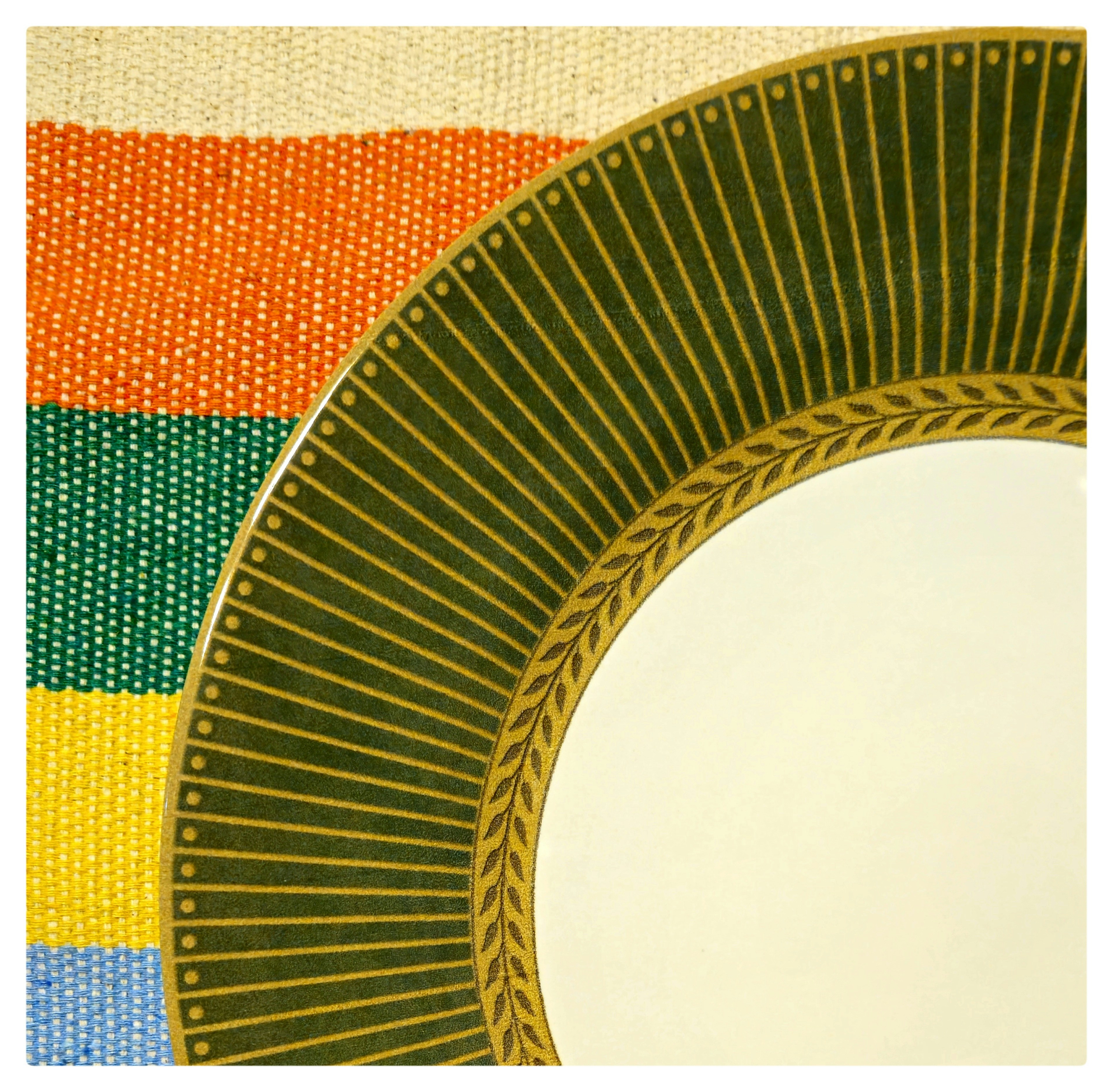 Edge of a gold-rimmed plate against a striped textile backdrop