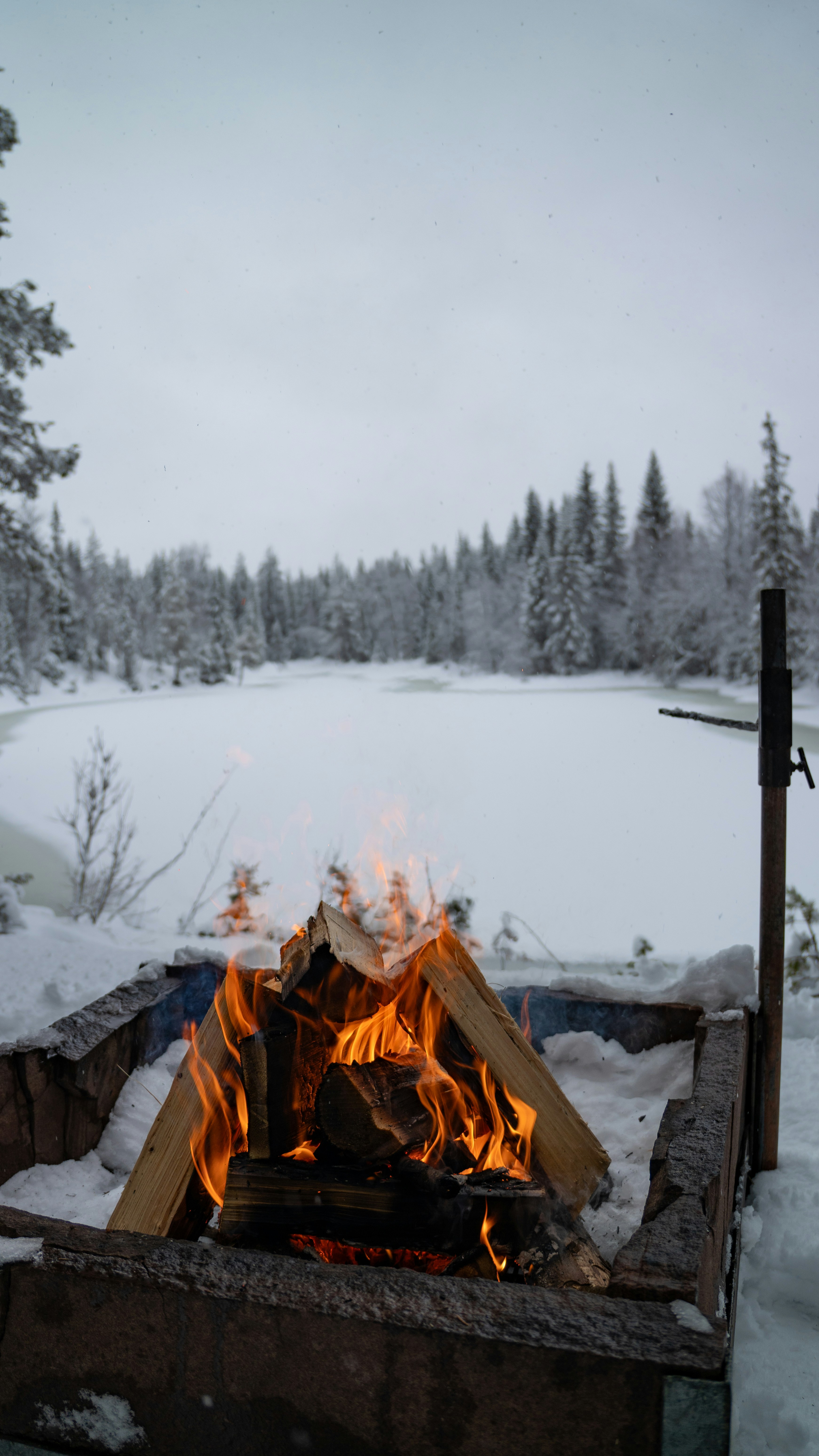 Campfire burning in the snow near a frozen lake. photo – Free Travel ...