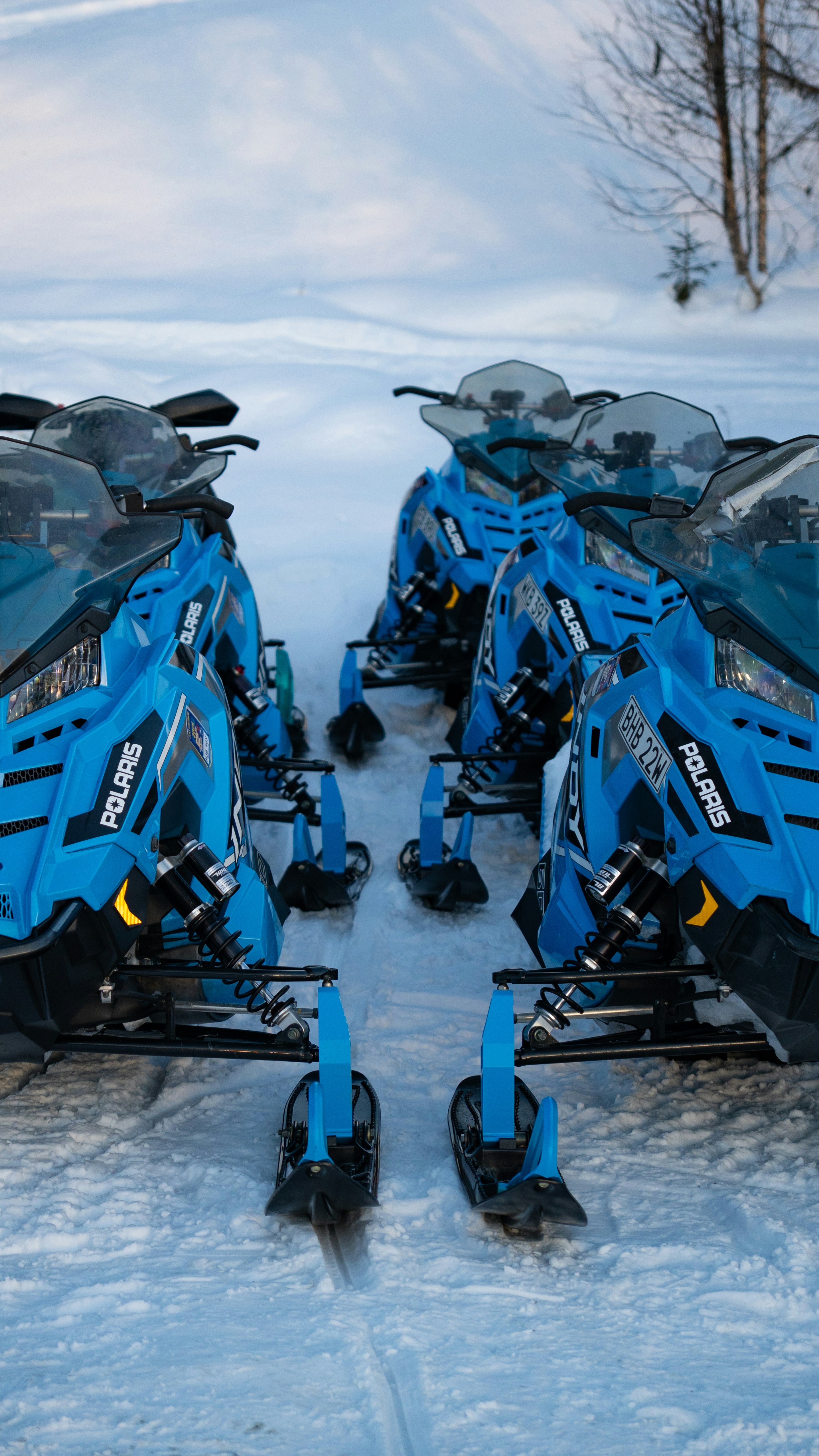 Blue Convoy in Frost: A Row of Polaris Snowmobiles in Powder Snow