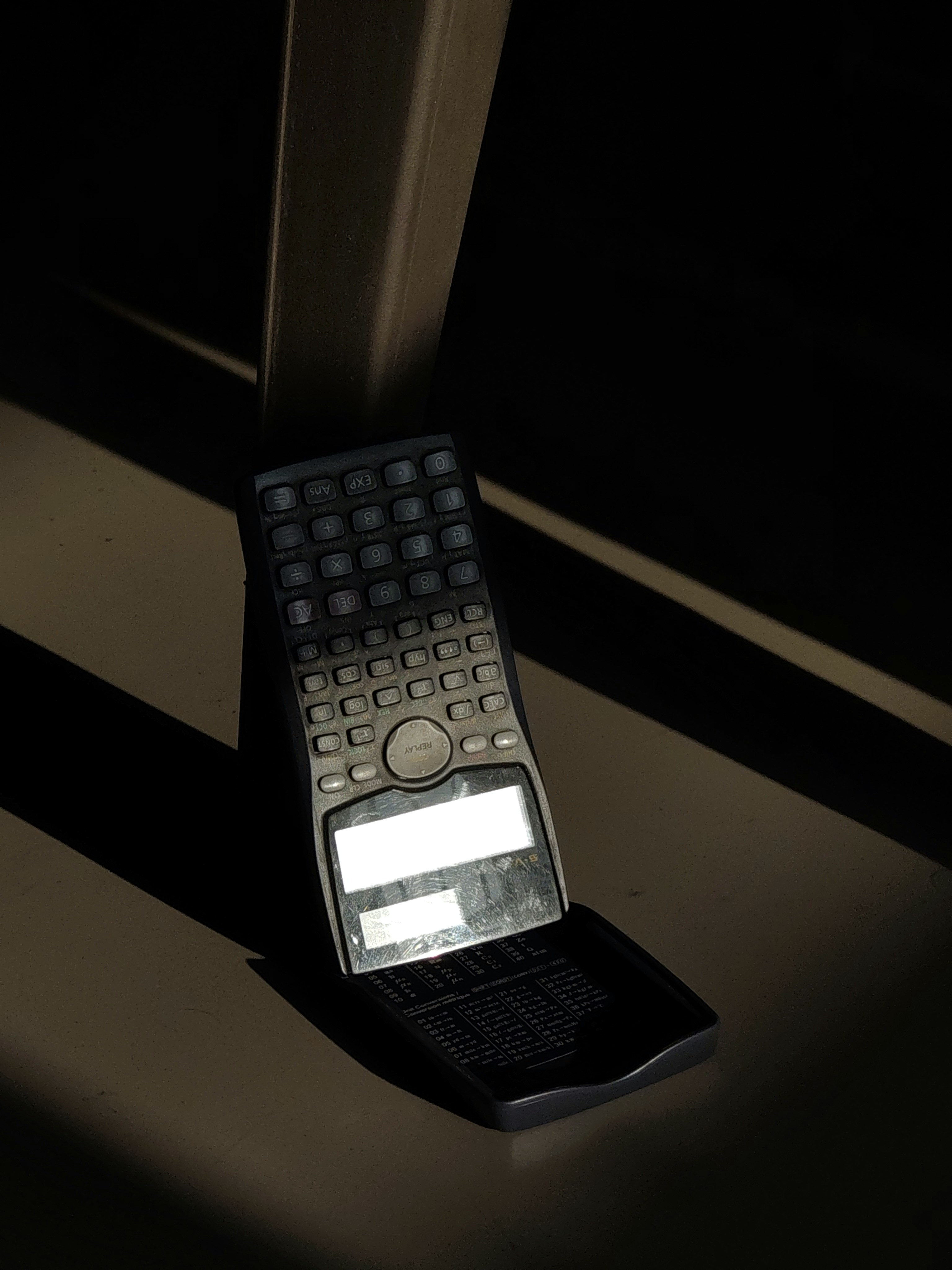 A scientific calculator rests in shadow