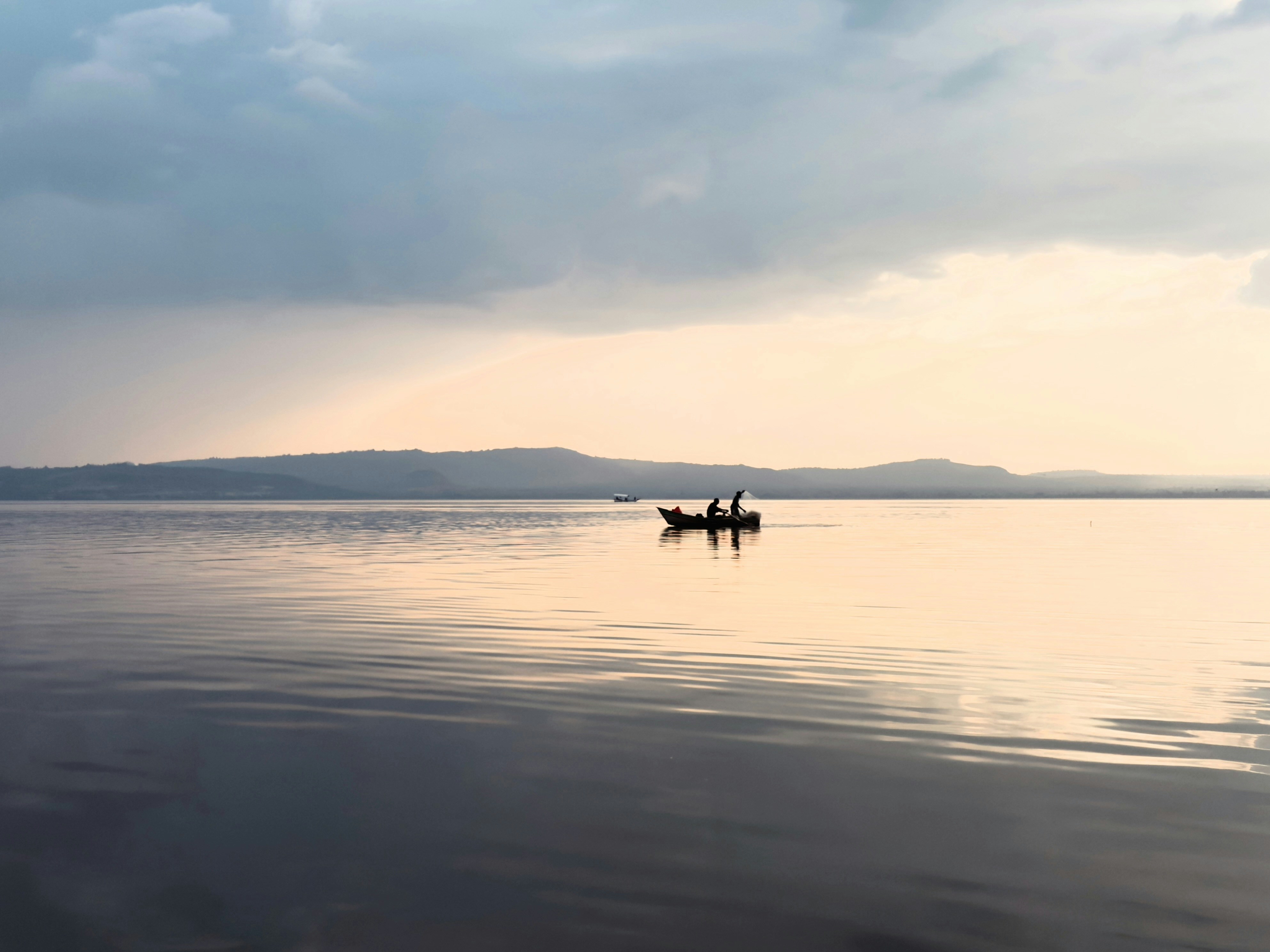 Dusk on a Glassy Lake: Two Figures Drift in a Quiet Boat