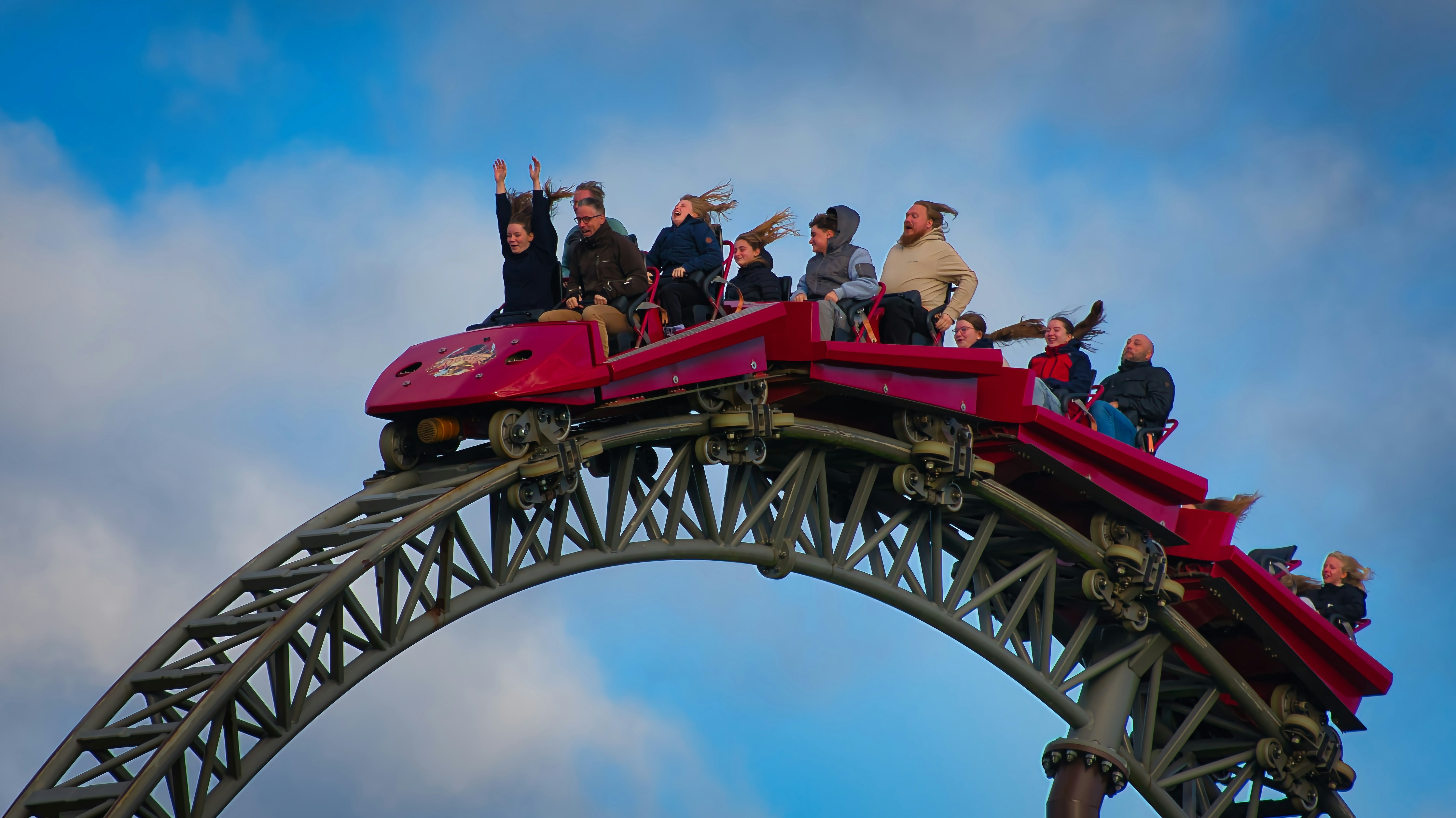 Crimson Coaster Crest: Riders Lean into the Arc Beneath a Clear Sky