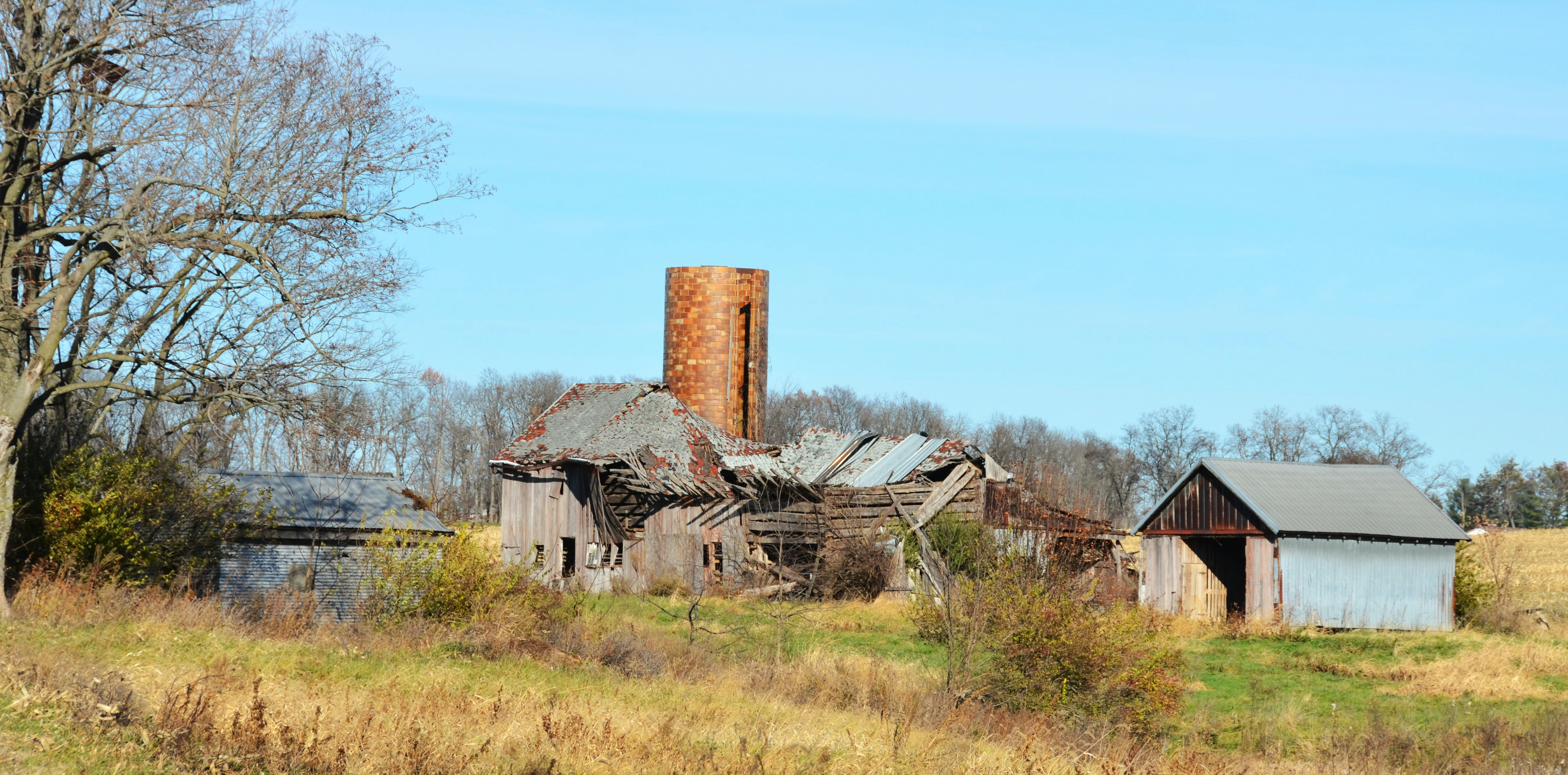 Weathered Silhouette: An Abandoned Farmstead Stands Against a Wide Prairie Sky