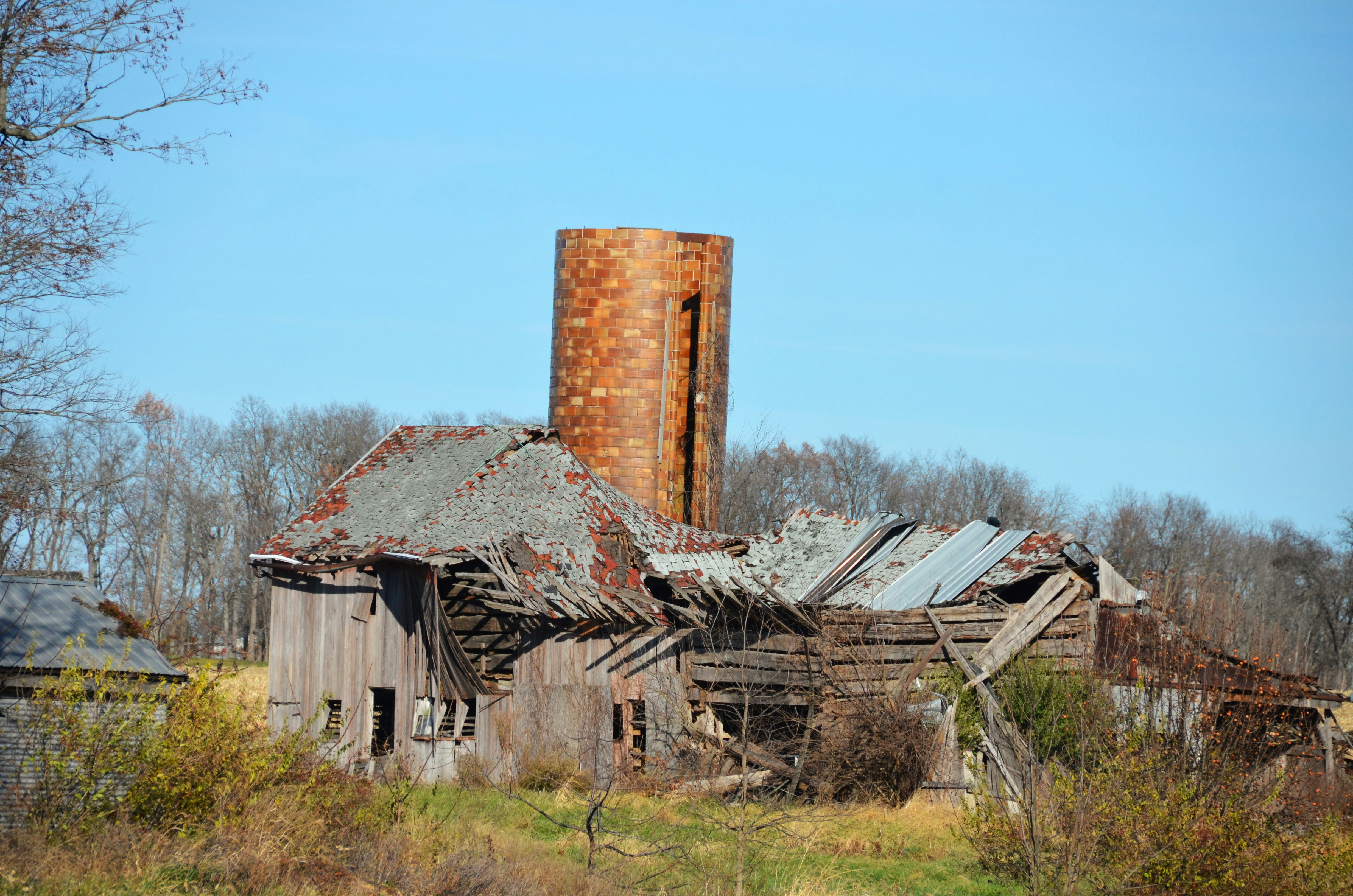 Rustbound Silo: A Crumbling Barn Under a Clear Blue Sky
