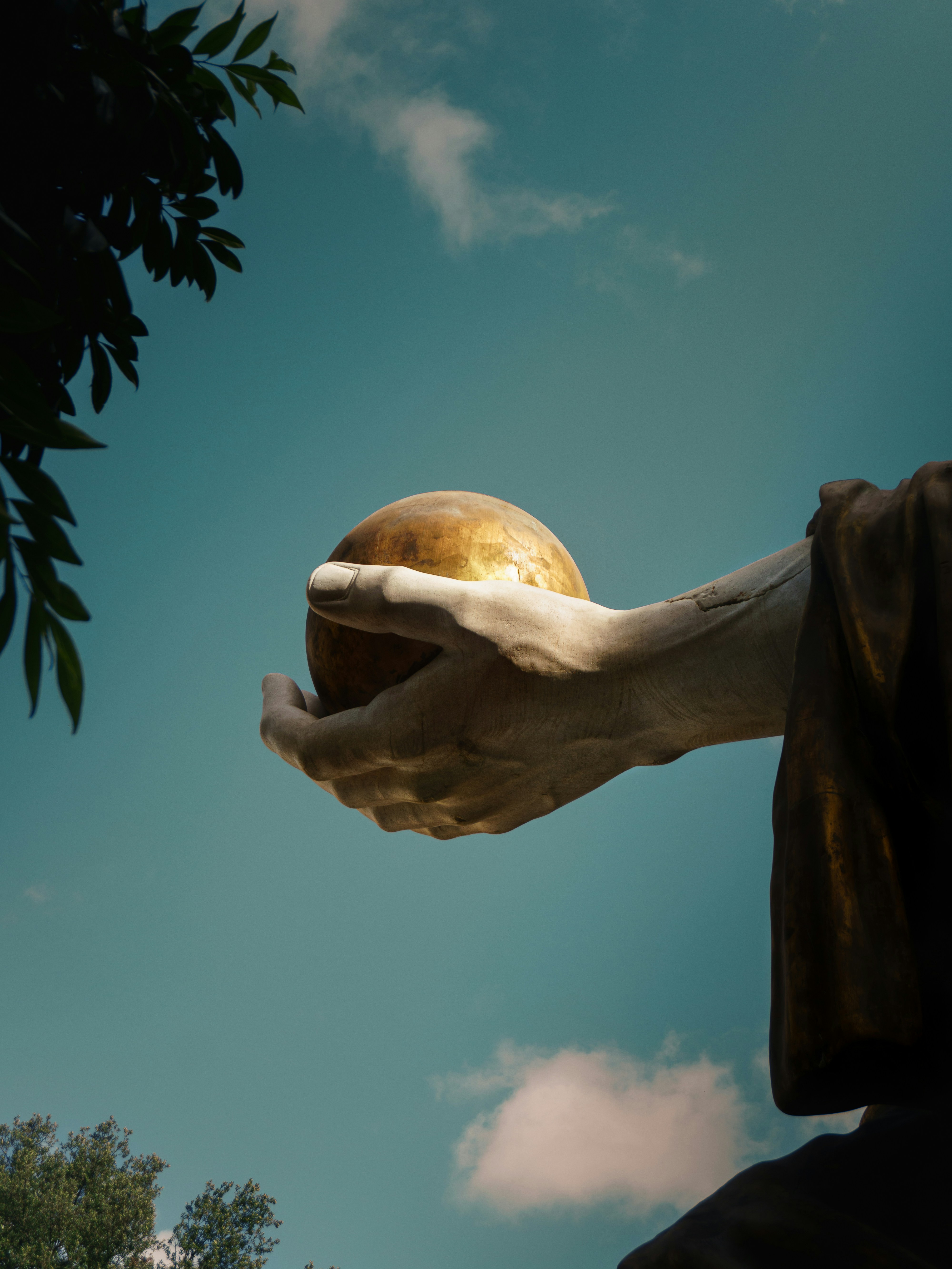 Gilded Embrace: A Giant Hand Cradles a Sunlike Sphere
