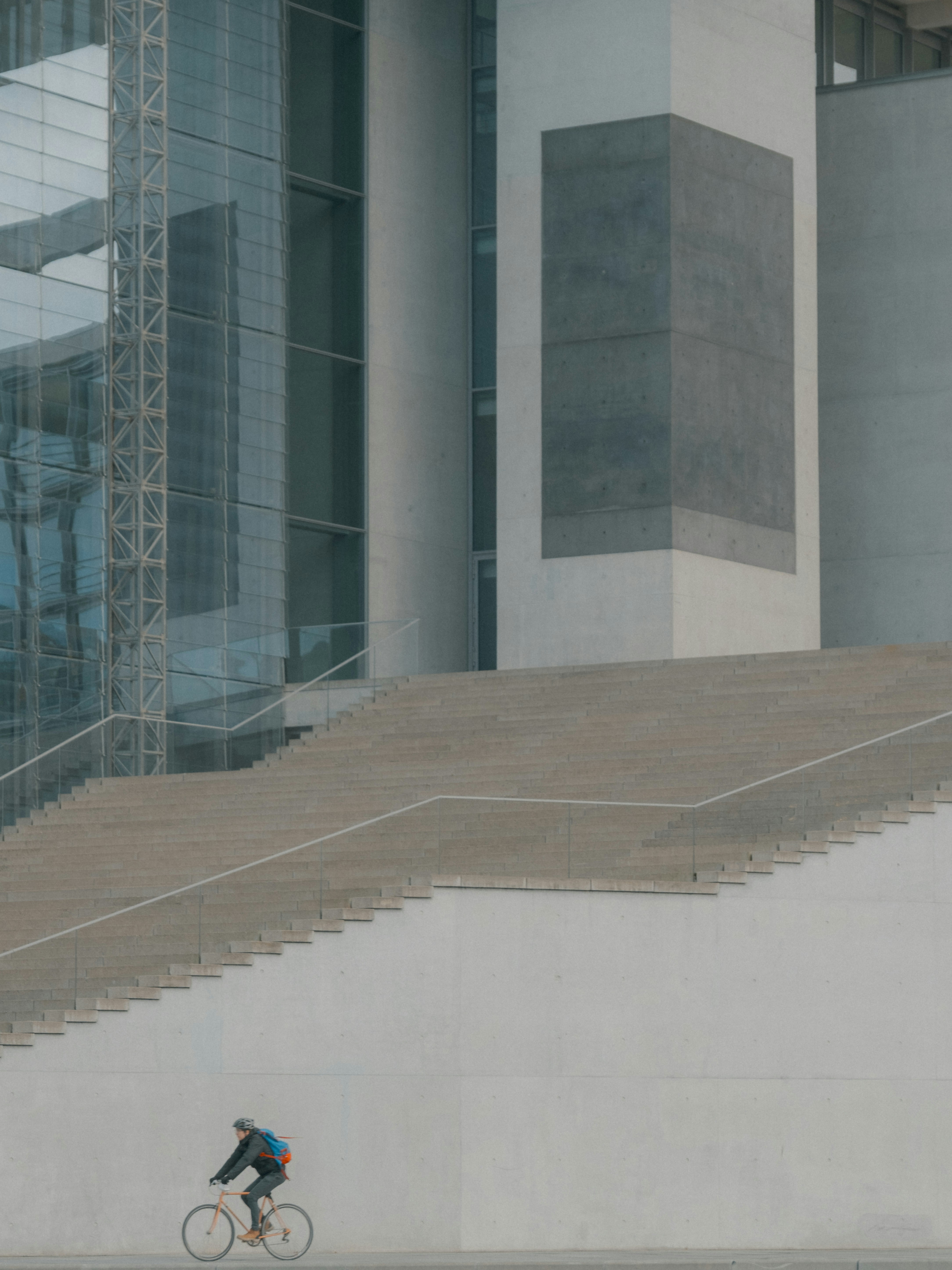 Lone Cyclist Carves a Line Across a Monolithic Concrete Plaza