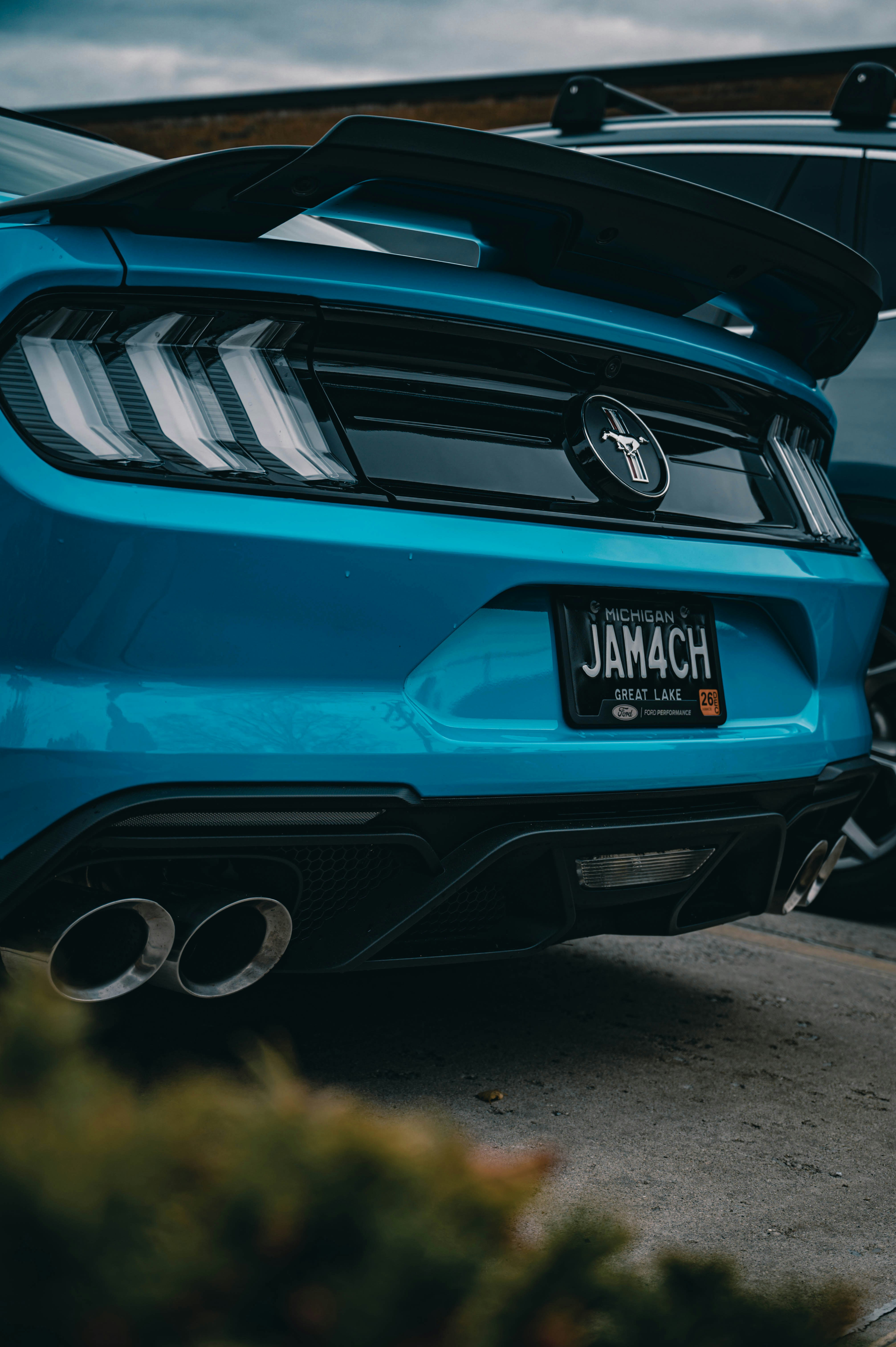 Azure Mustang Rear View: Emblem, Spoiler, and Quad Exhausts in a Parking Lot